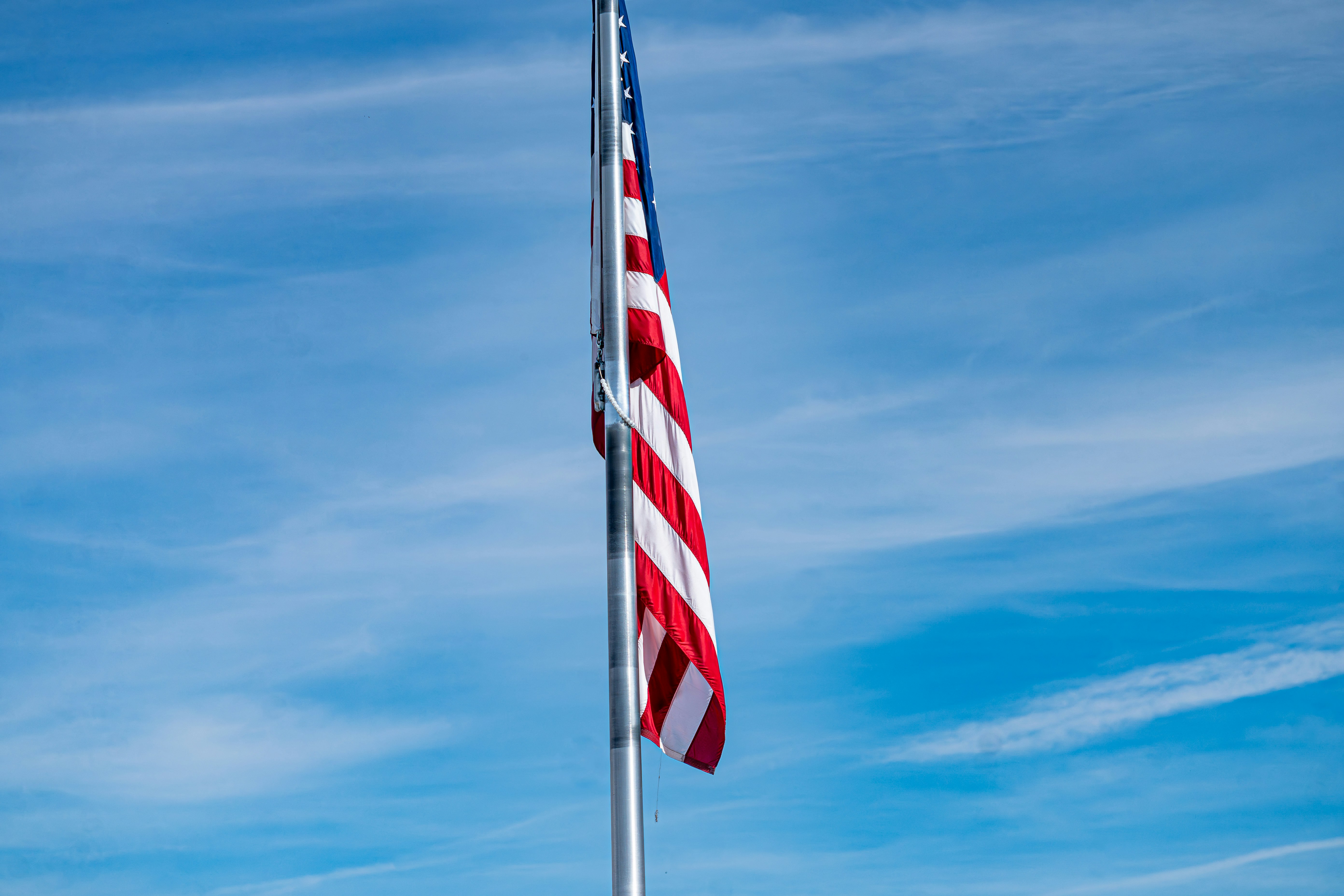 Pole Veil: An American Flag Rippling Against a Clear Sky