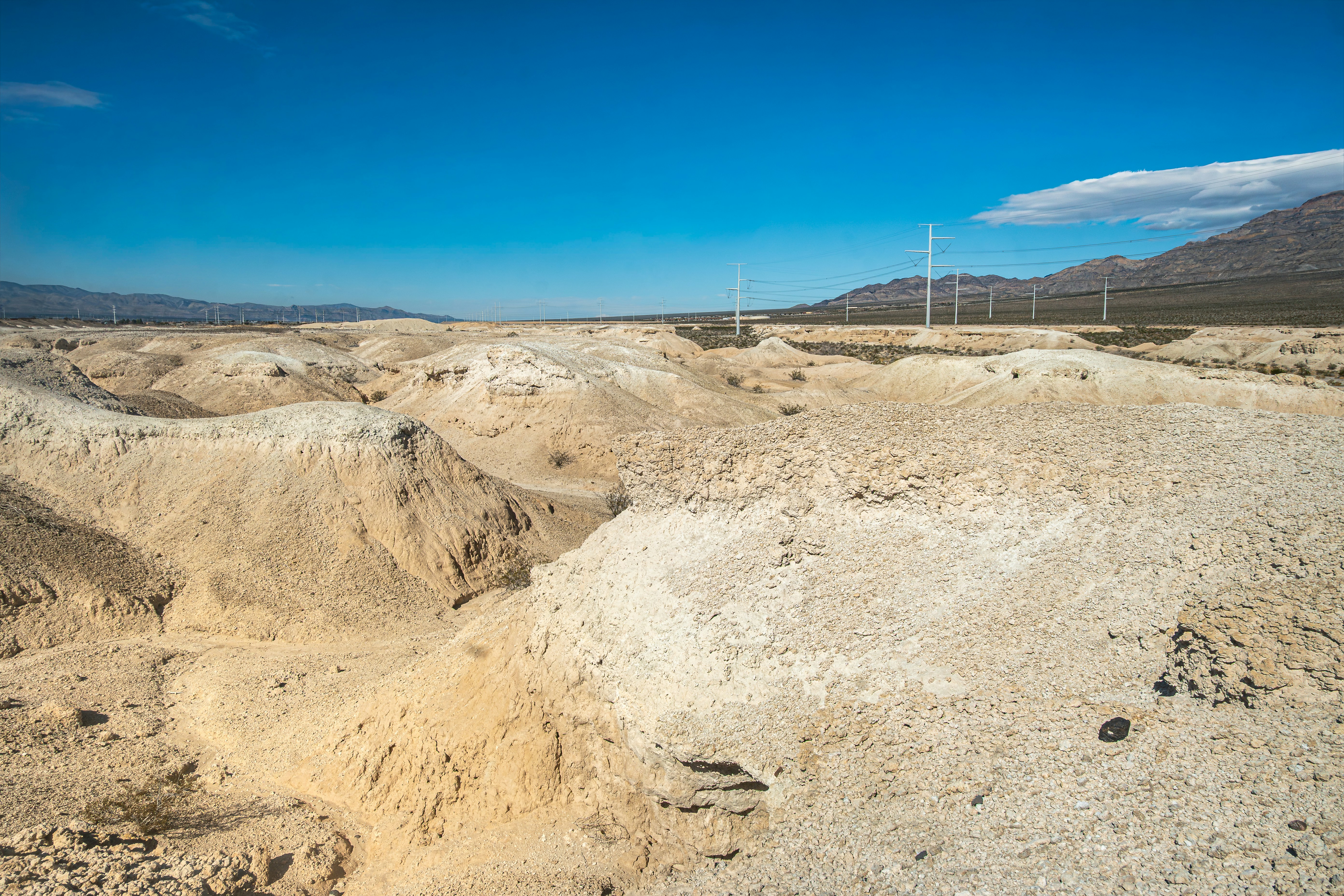 Desert Terrain Under a Clear Blue Sky with Distant Power Lines