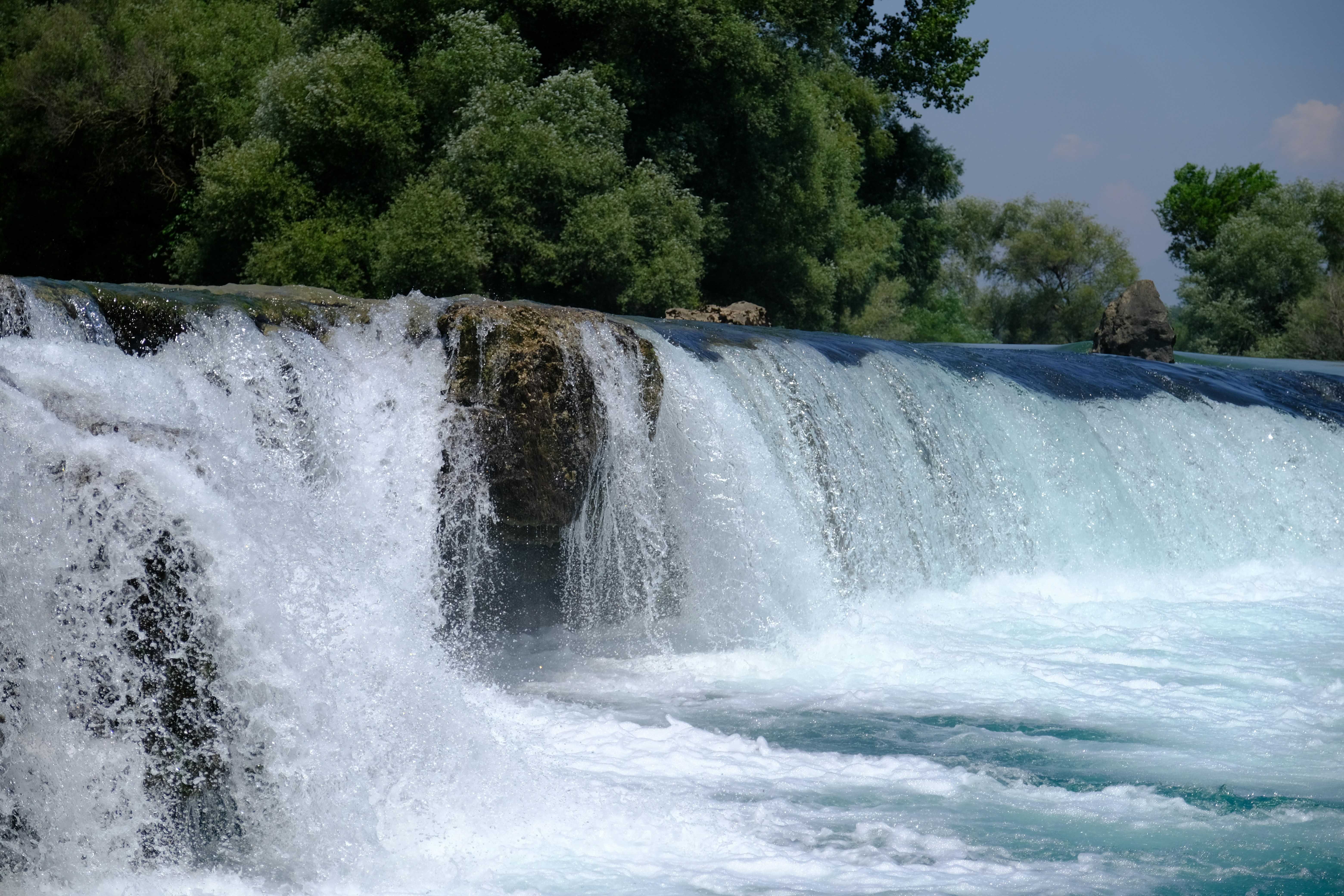 Cascading Veil: Midstream Waterfall Across a Turquoise River