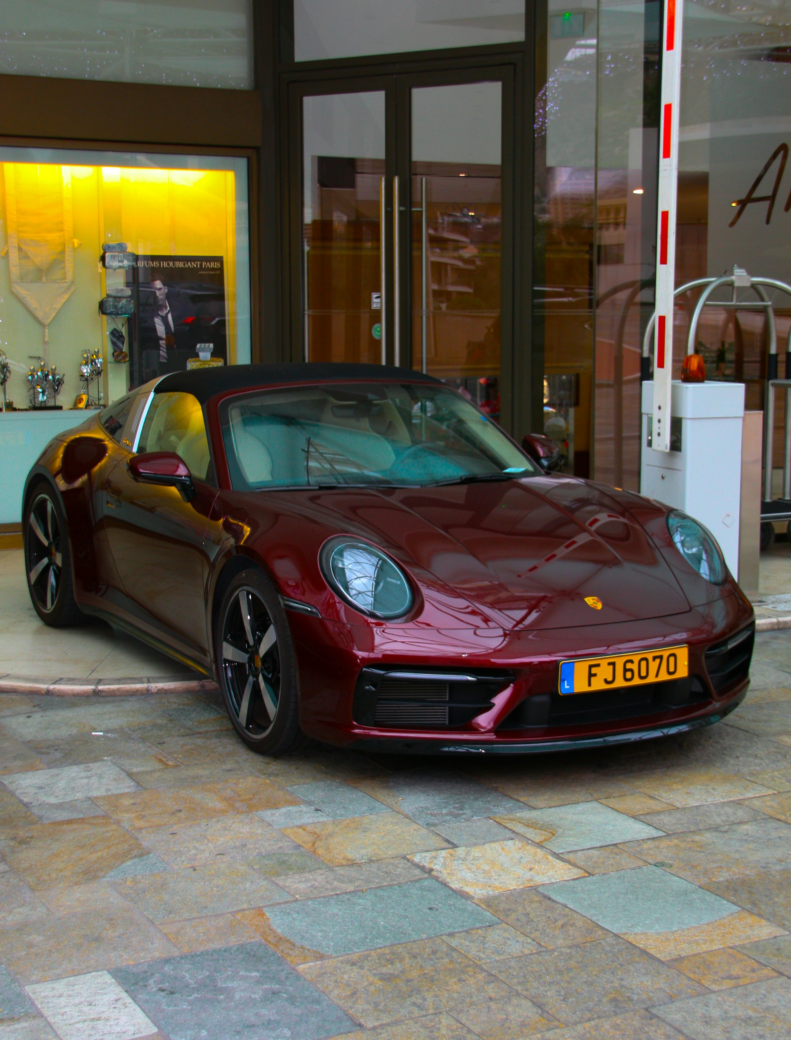  burgundy Porsche parked at luxury shop doorway