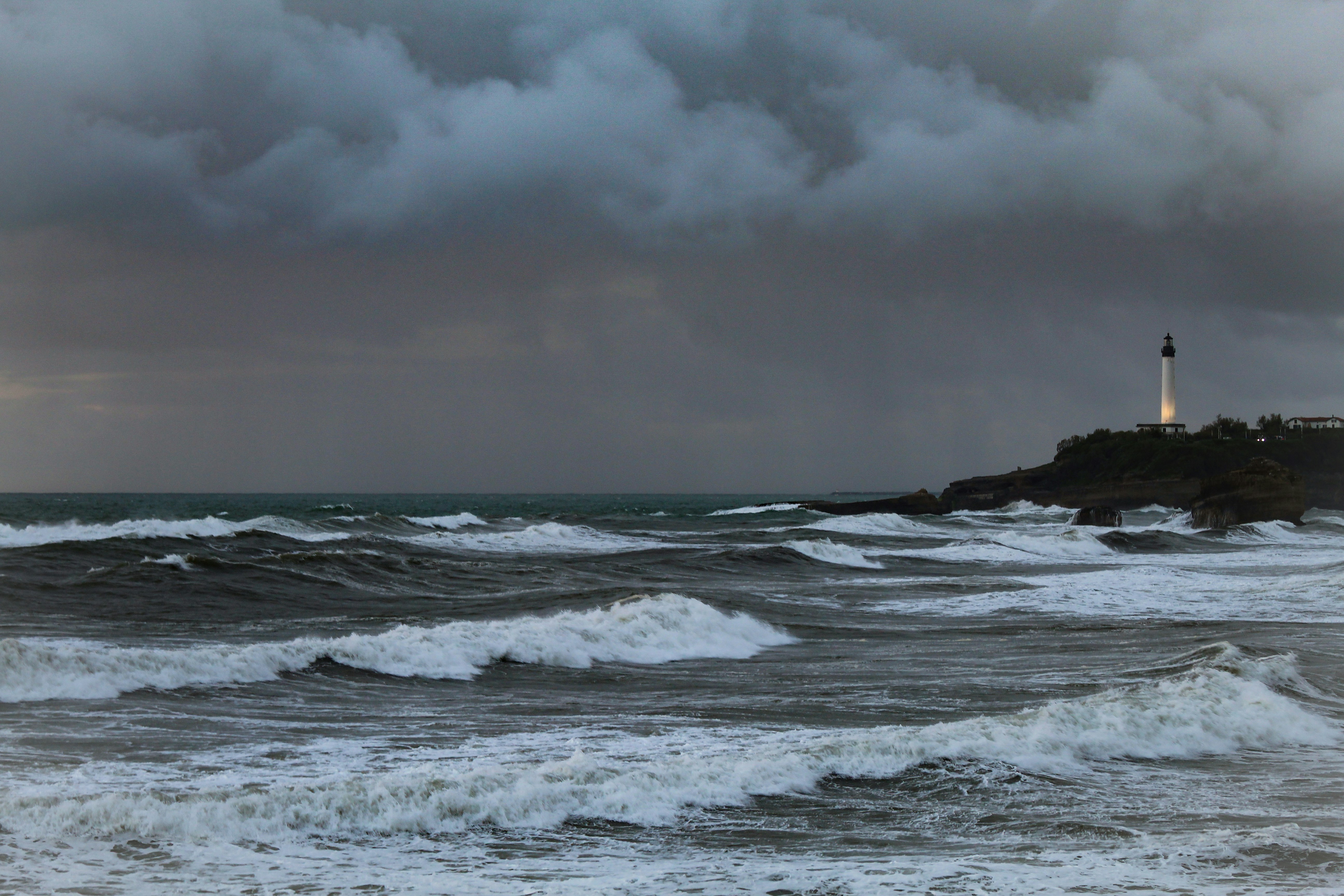 Lighthouse on the Crest: Stormy Sea at Dusk