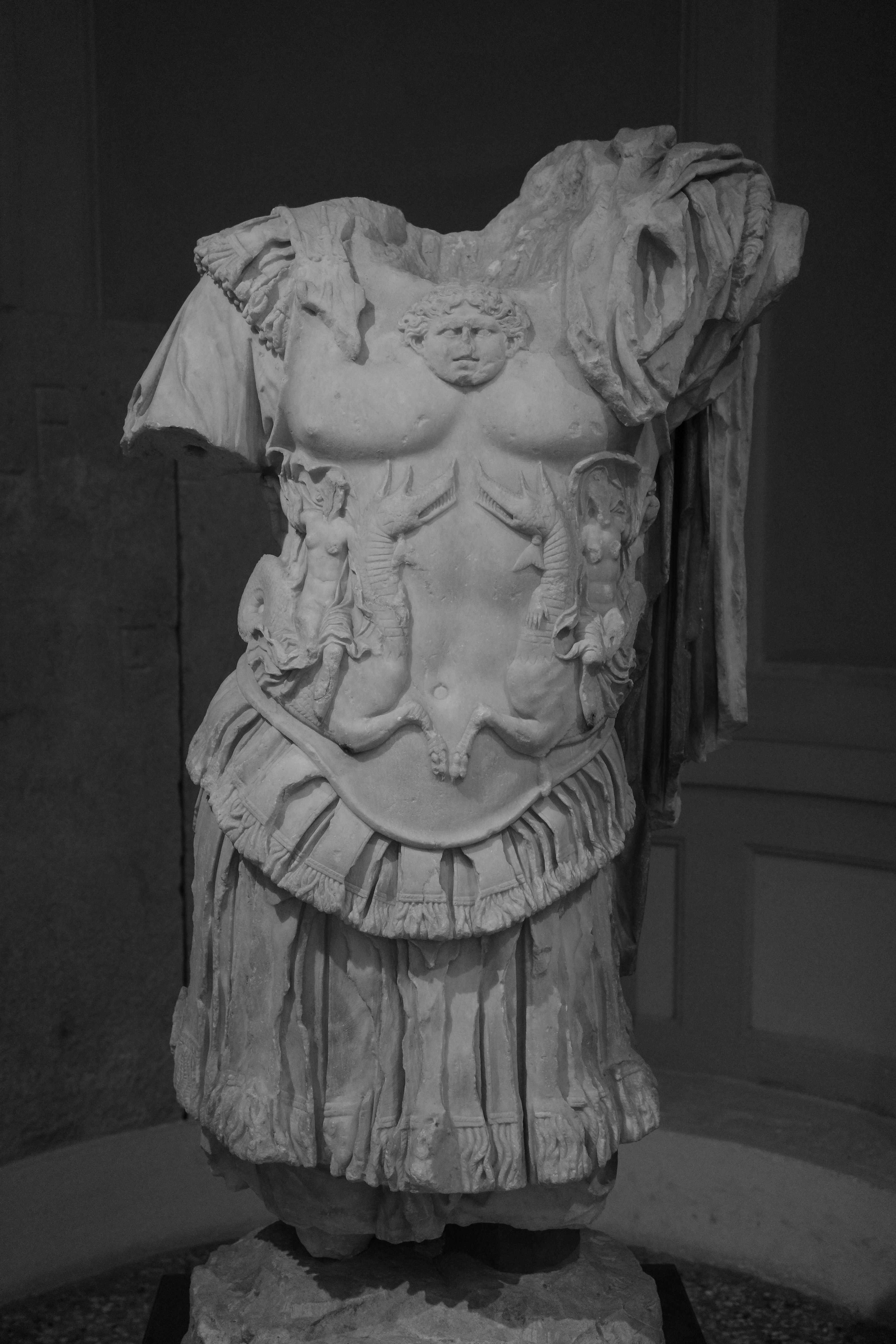 Weathered torso of a draped statue: carved emblem and figures