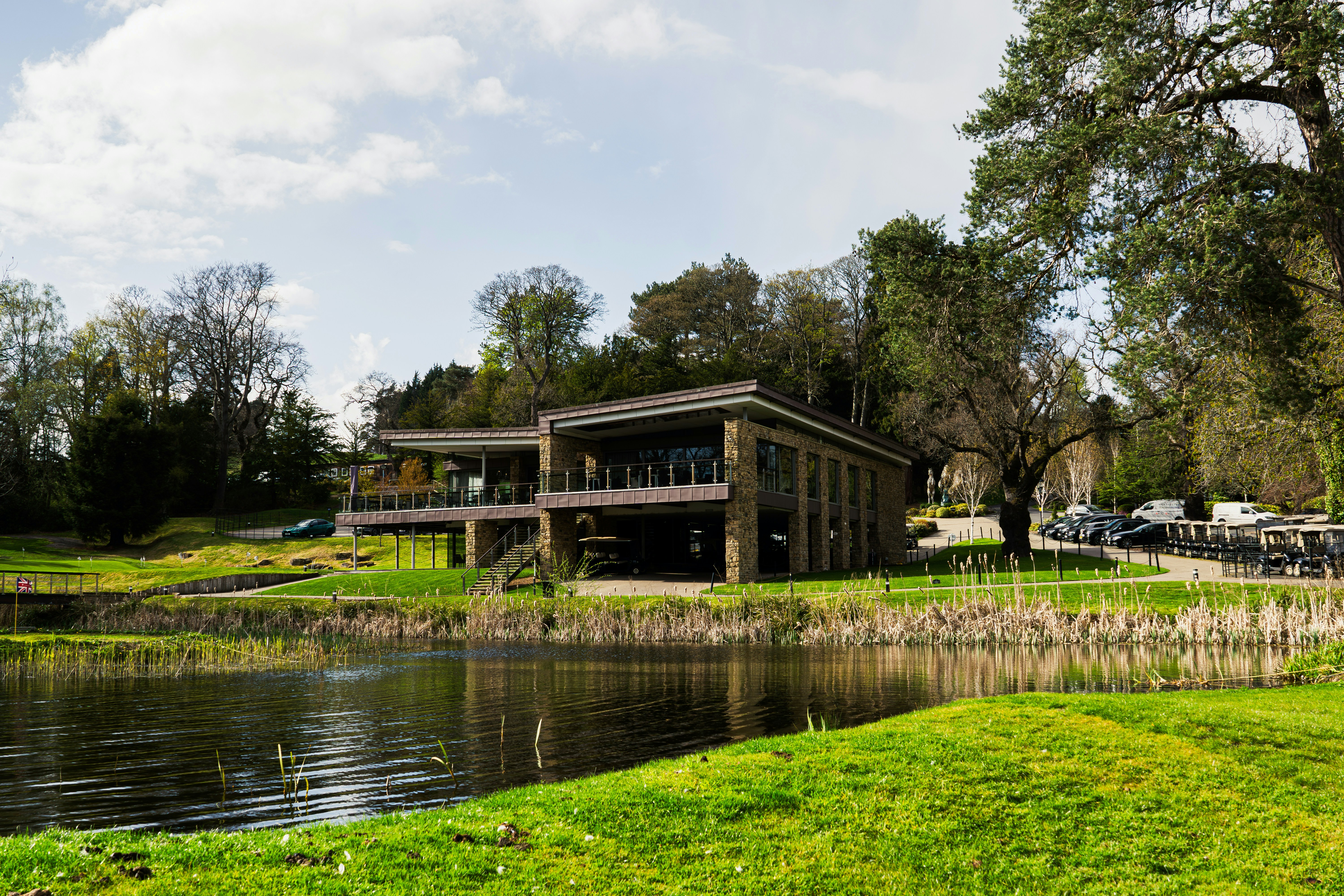 Glassy pond, brick pavilion, and green lakeside in dappled sunlight