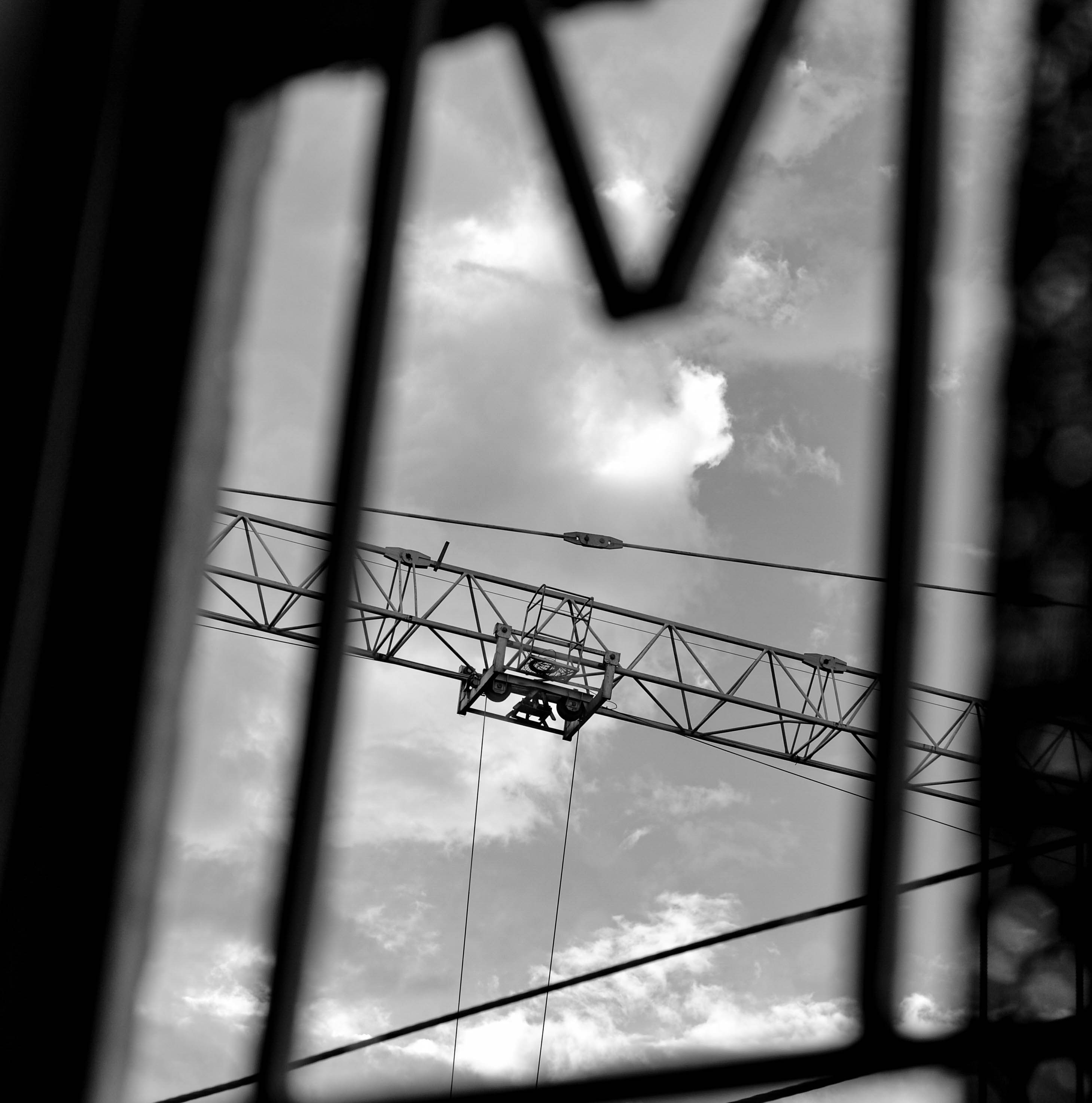 Suspended Crane Silhouette Behind Railroad Grid