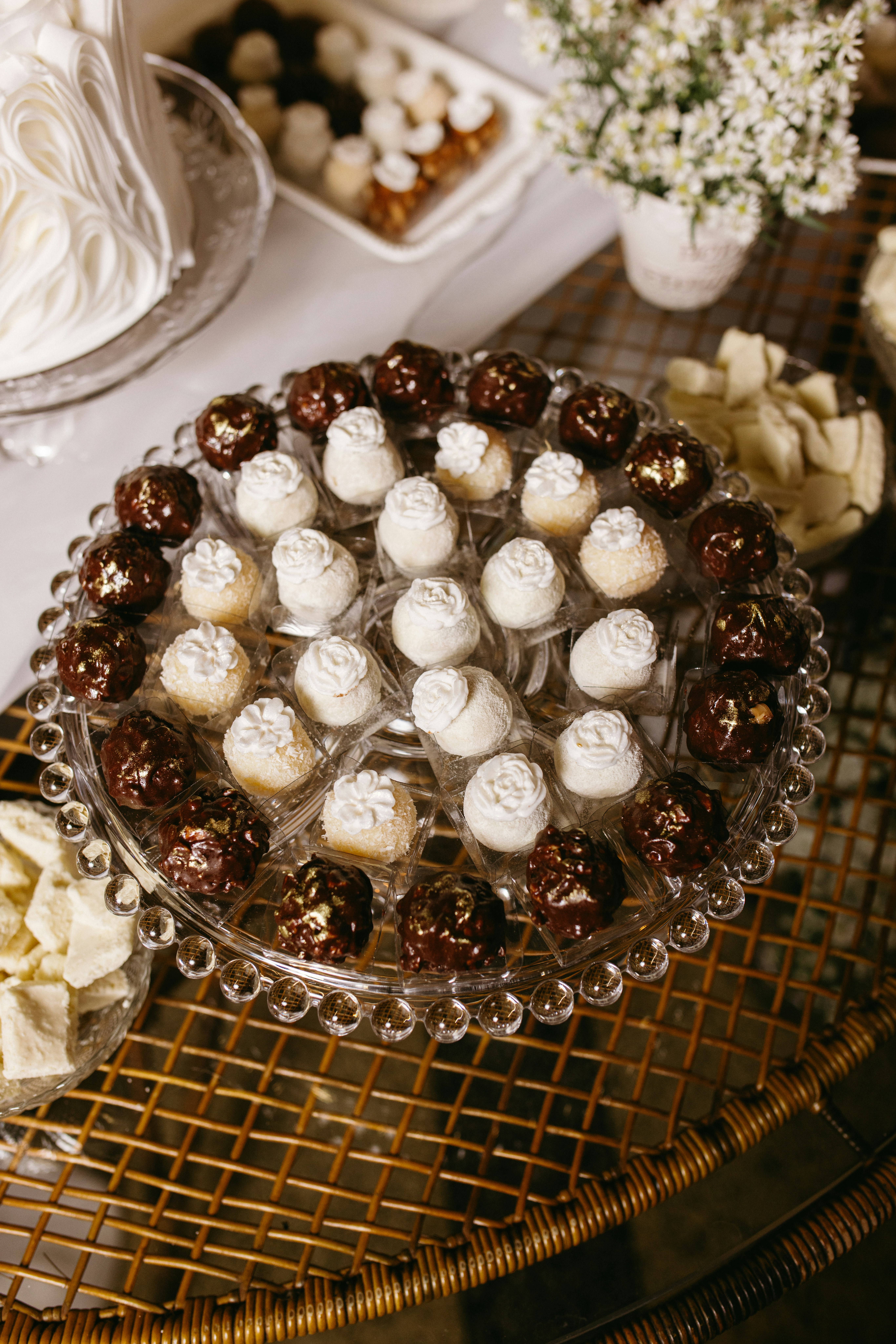 Glass pedestal of bite-sized chocolate and vanilla truffles on a dessert table