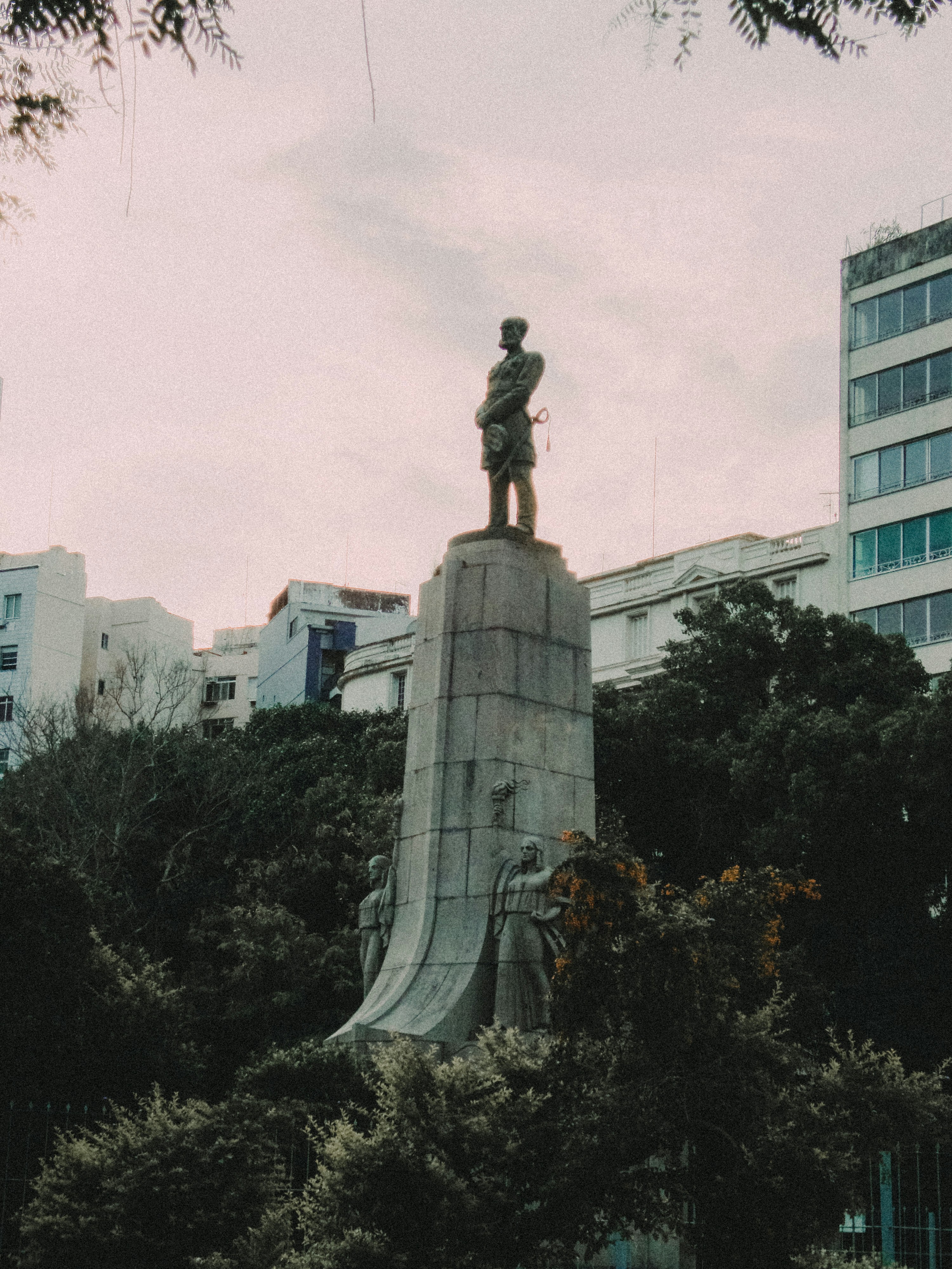 Statue on a Stone Pedestal Surrounded by Urban Foliage