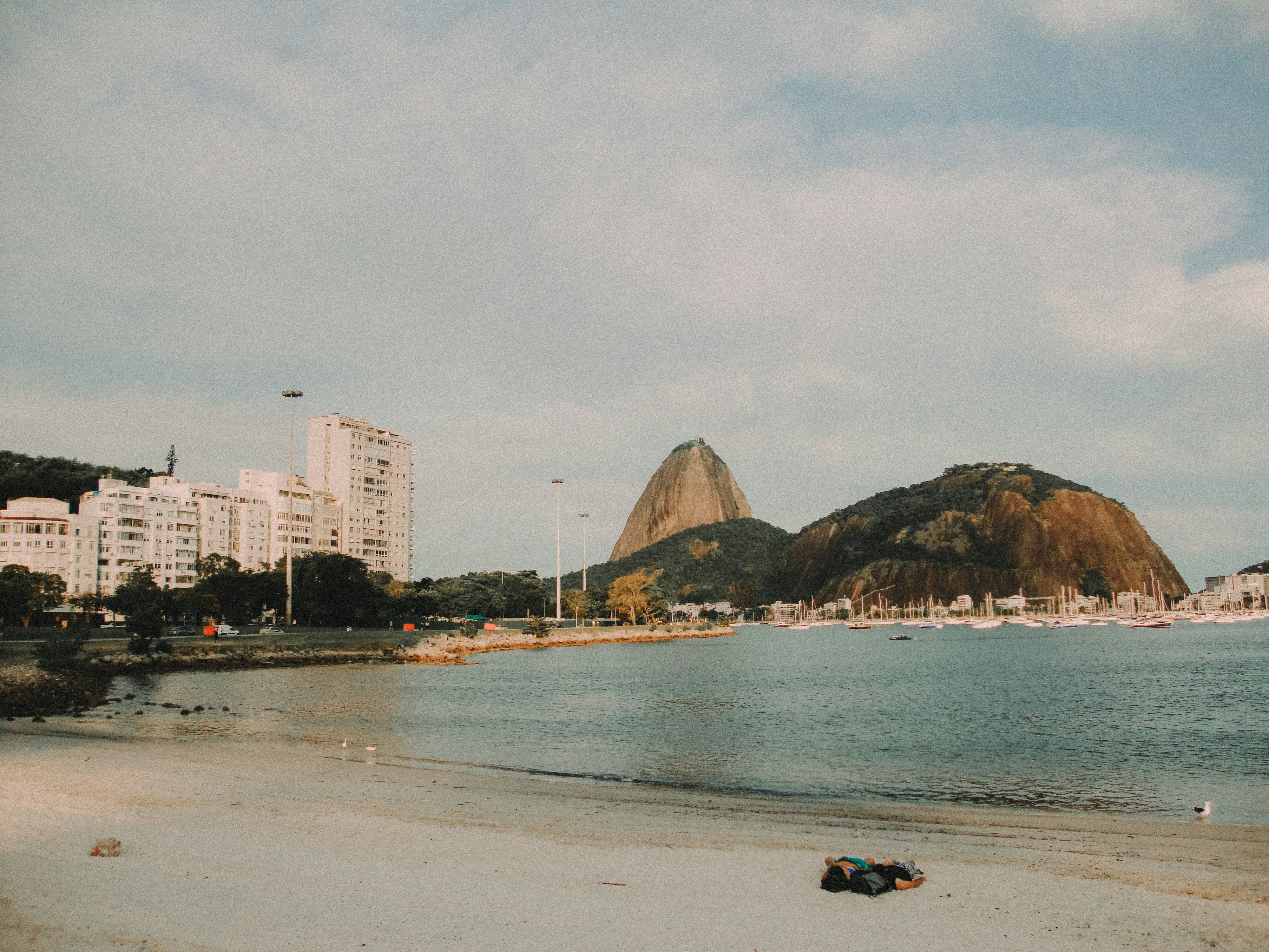 Harbor Edge: A Quiet Beachfront with Distant Hills and Urban Silhouette