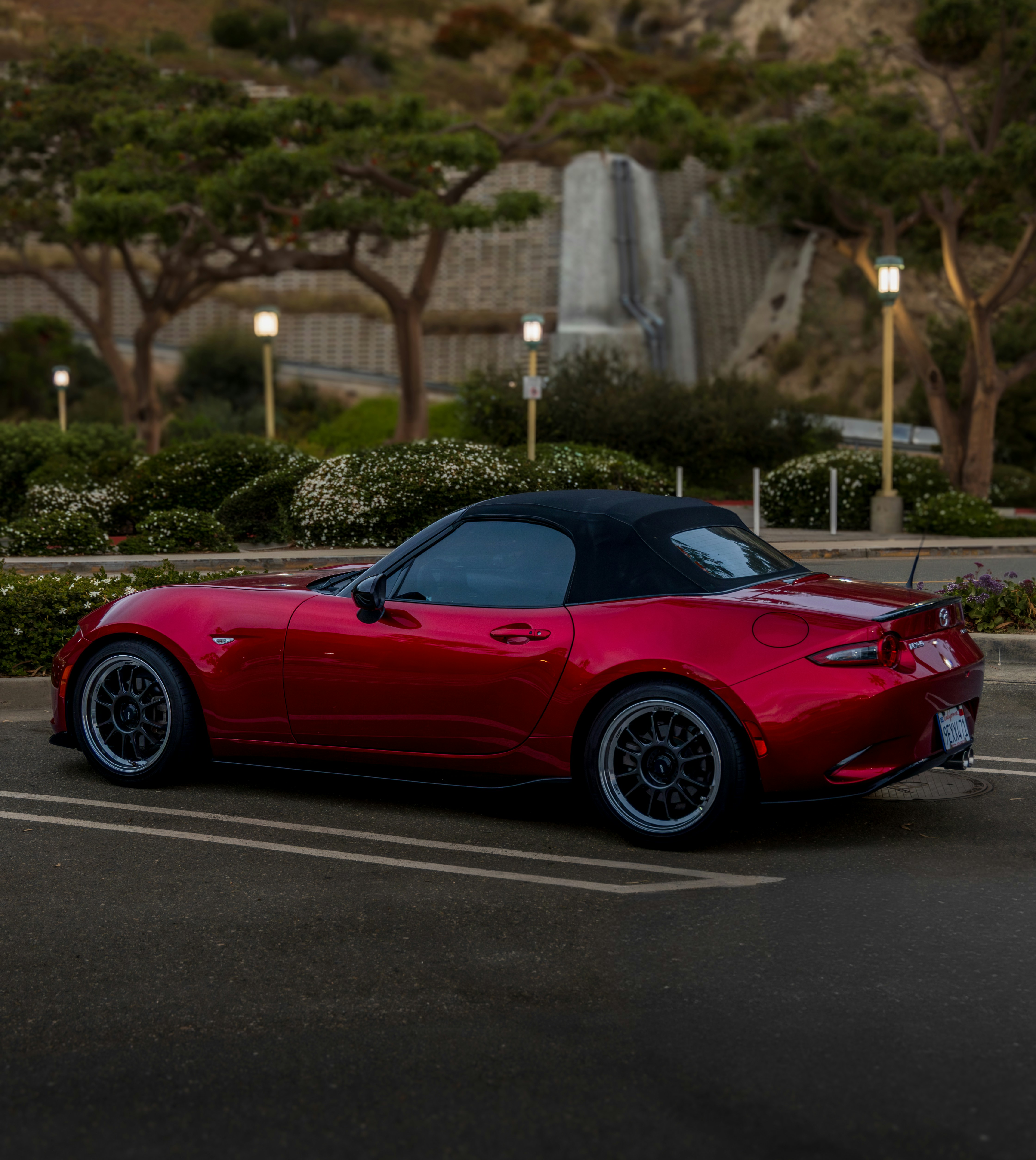 Red Convertible in a Quiet Parking Lot Framed by Landscape