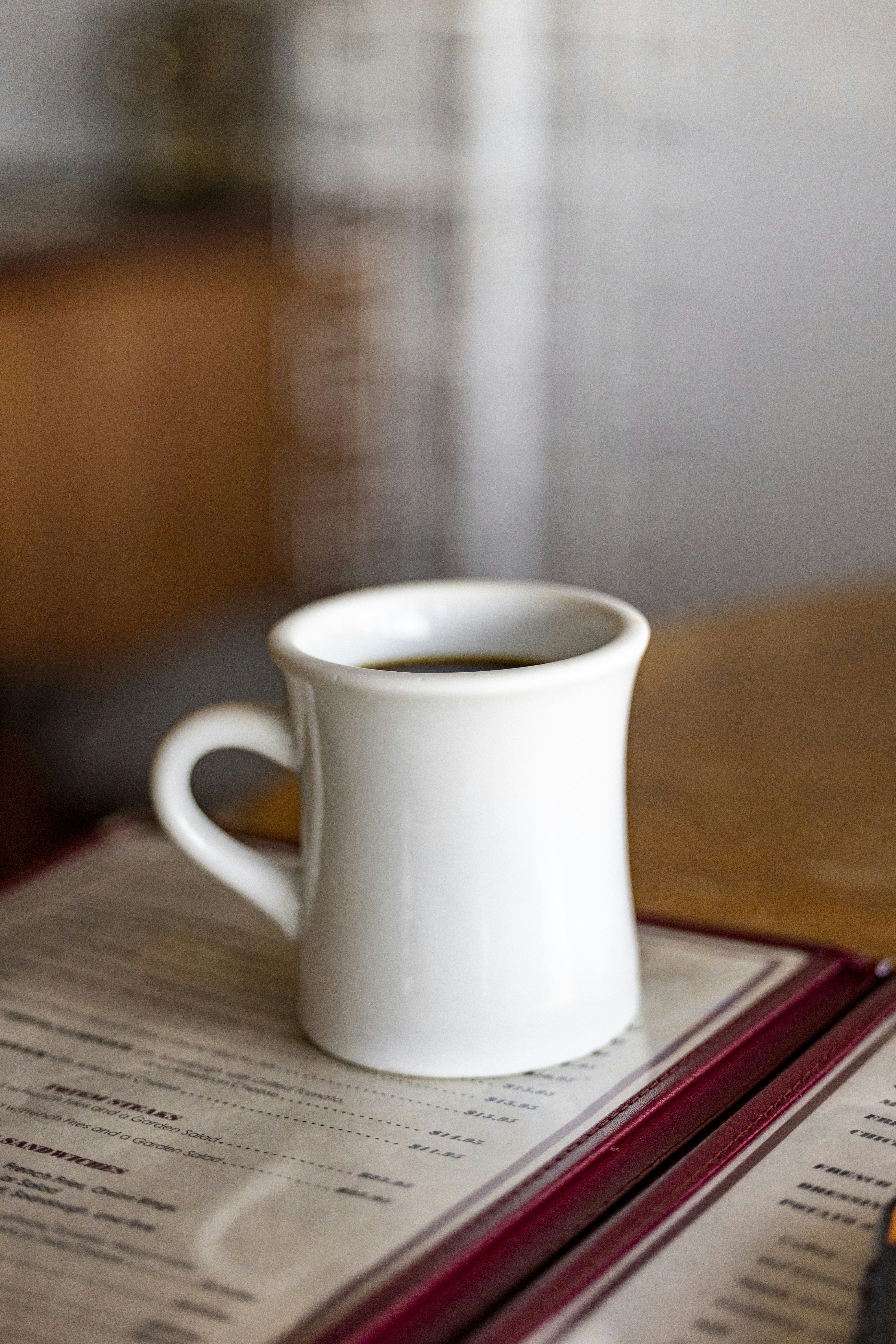 Steam and Simplicity: A White Coffee Mug Centered on a Menu
