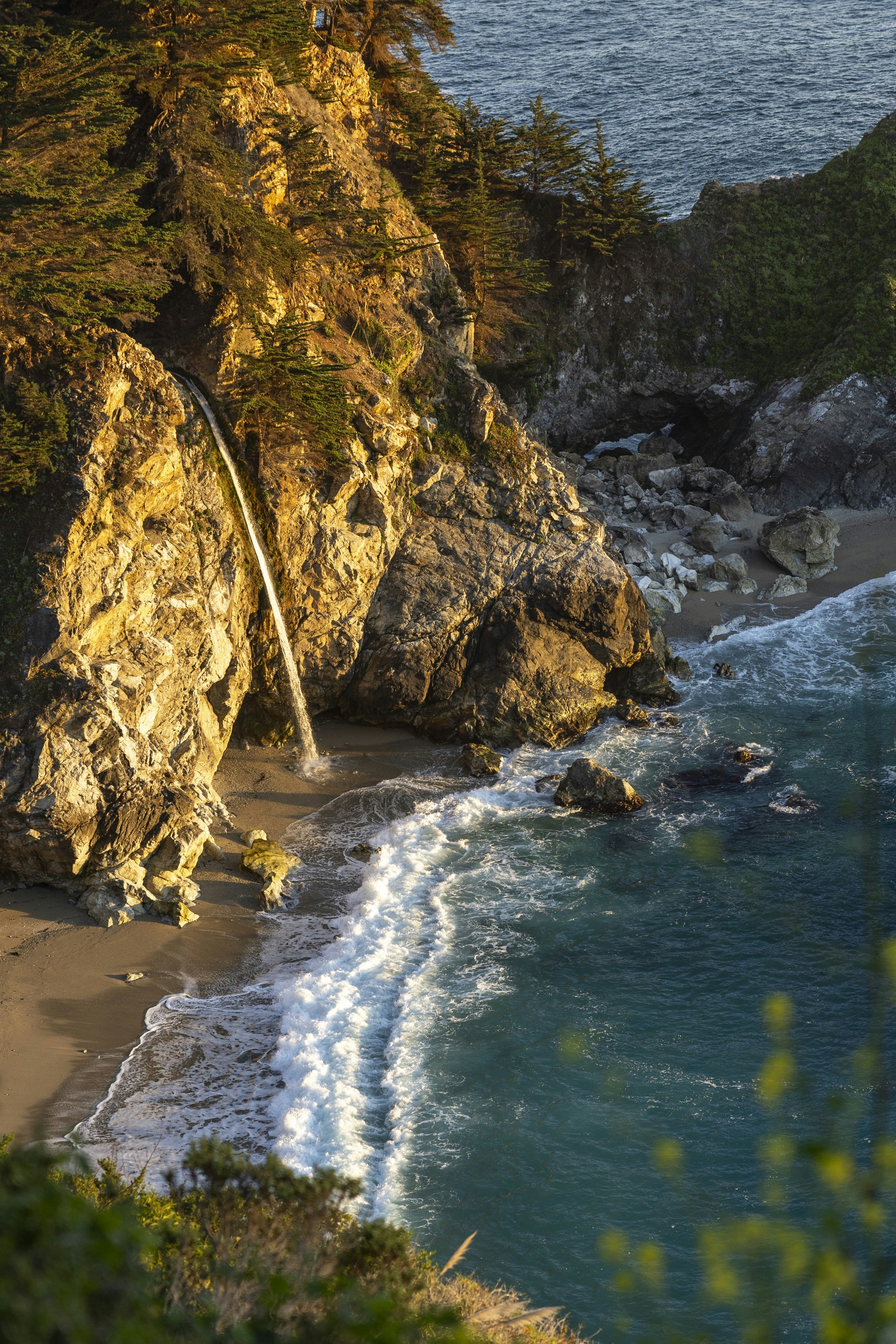 Sunlit Cliffside Cascade Drops into Turquoise Cove