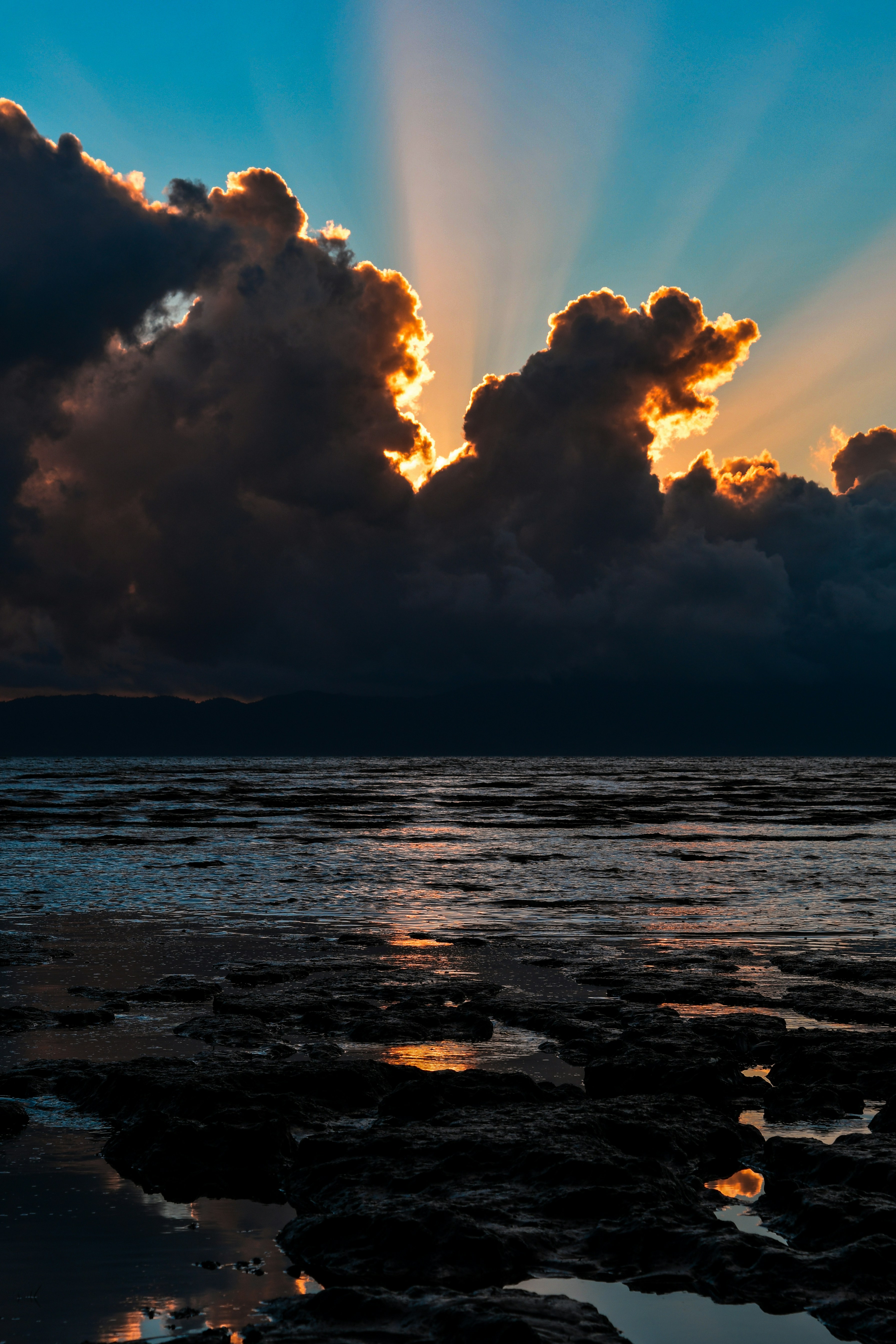 Sunburst Among Rain Clouds Over a Quiet Tidal Plain