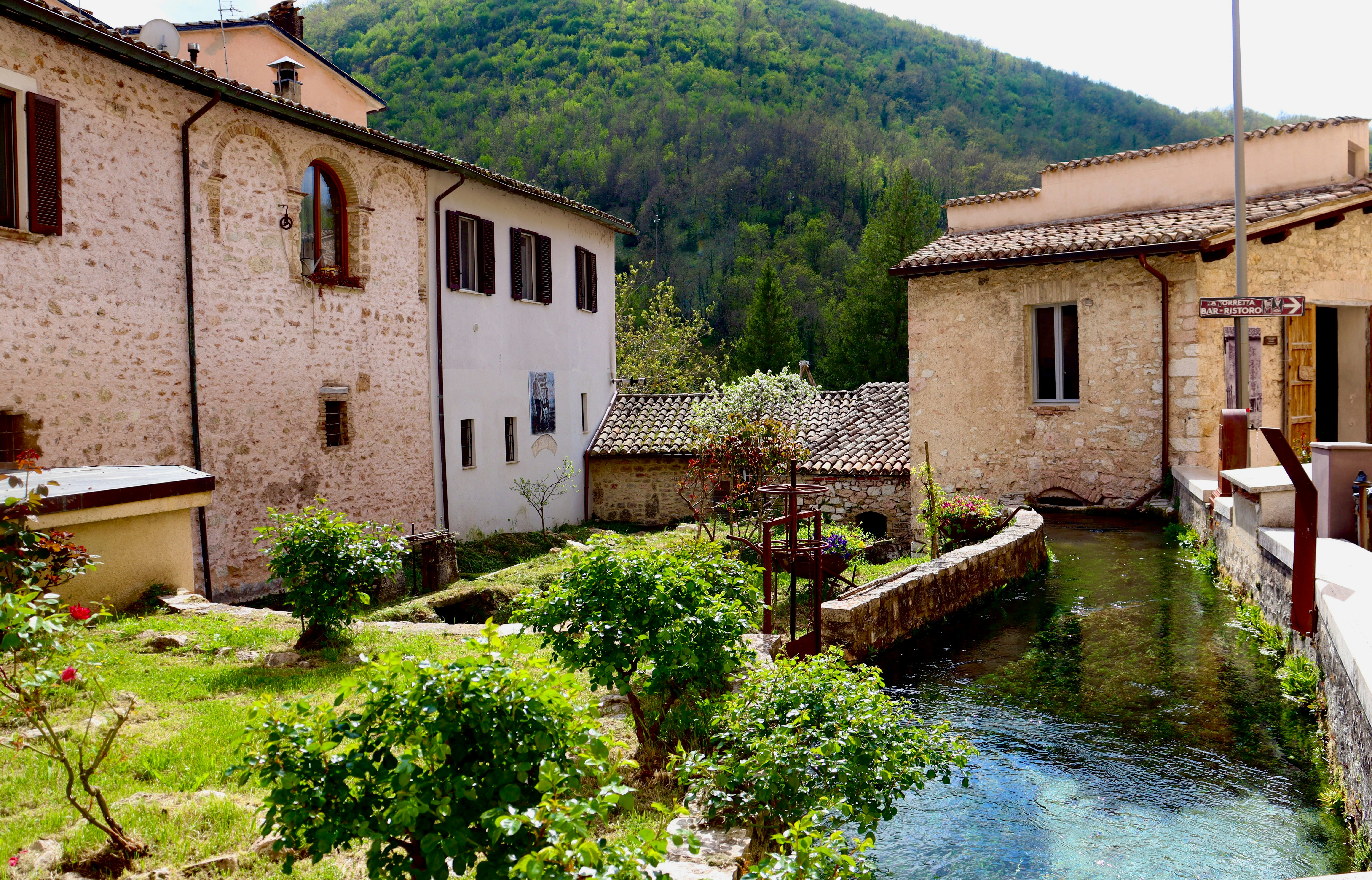 Sunlit stone village with a tranquil canal weave
