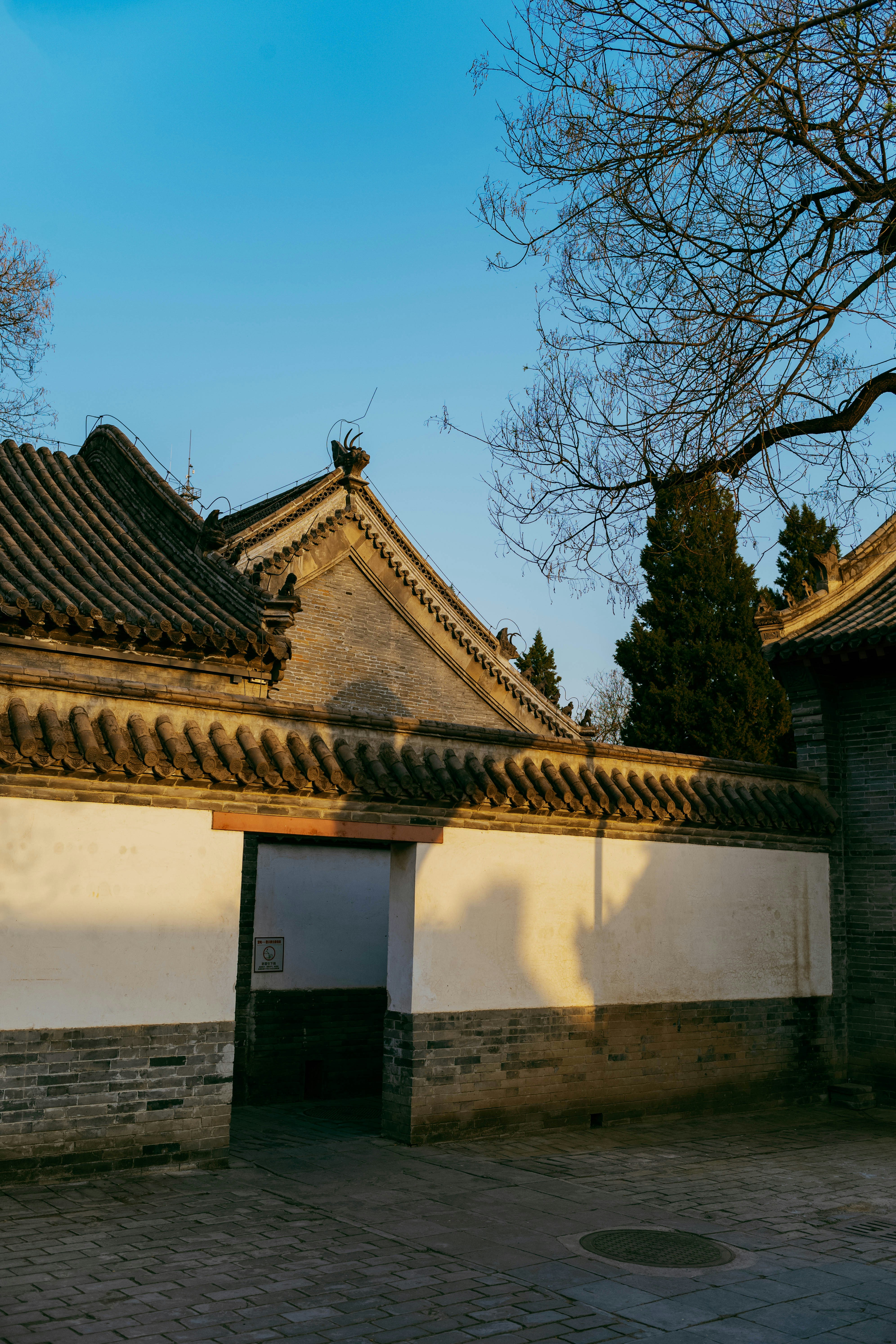 Sunlit Courtyard Wall and Roofline Against Clear Sky