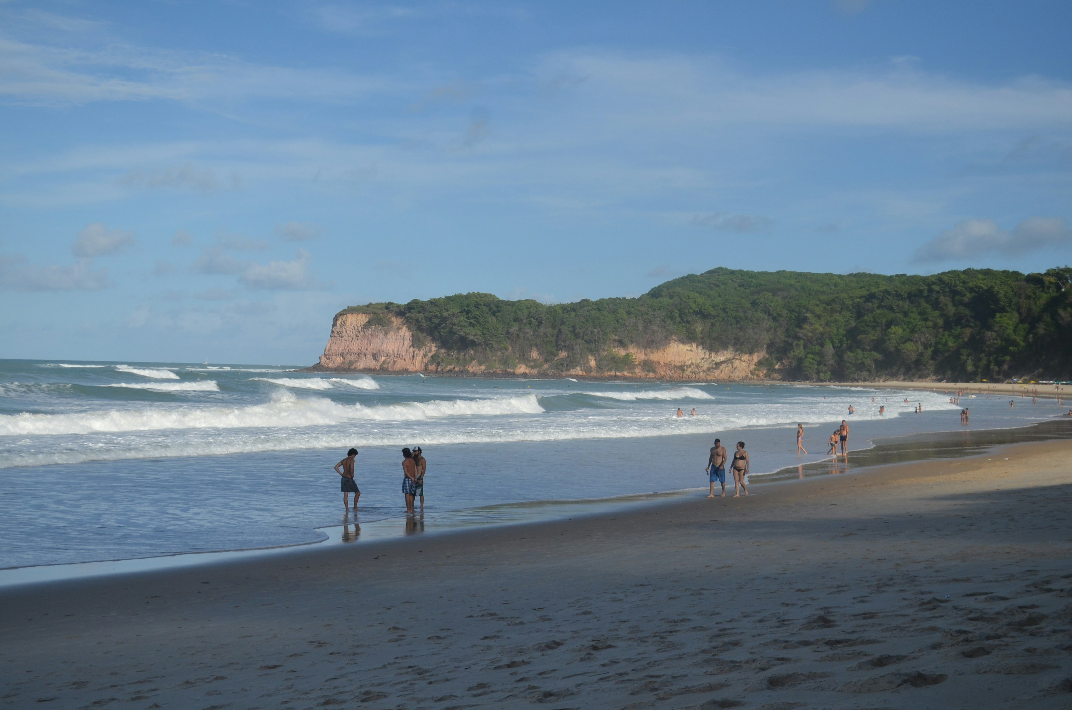Beach gathers in soft morning light as surfers and families explore the shoreline