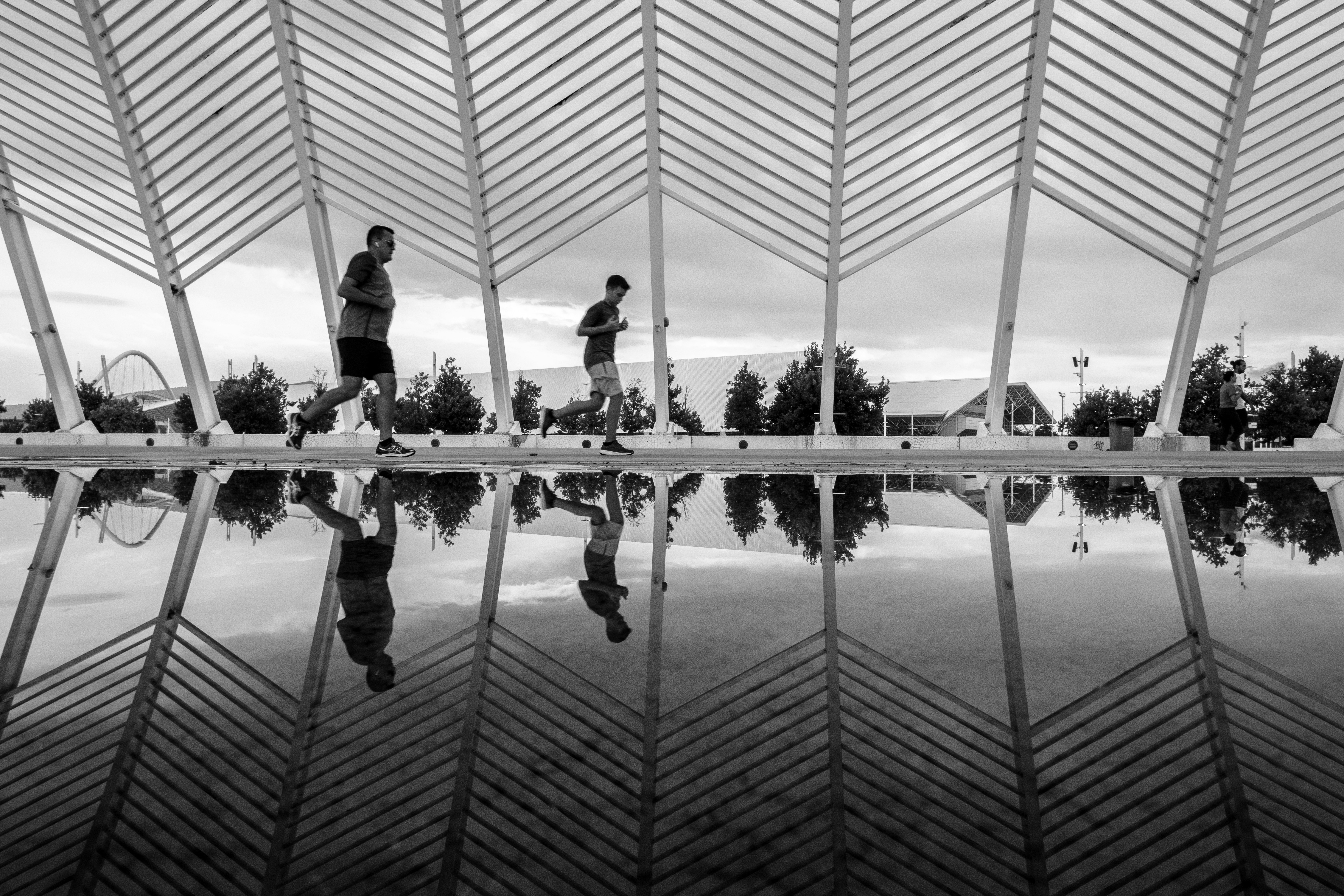 Tide of Mirrors: Joggers Beneath a Pleated Sky