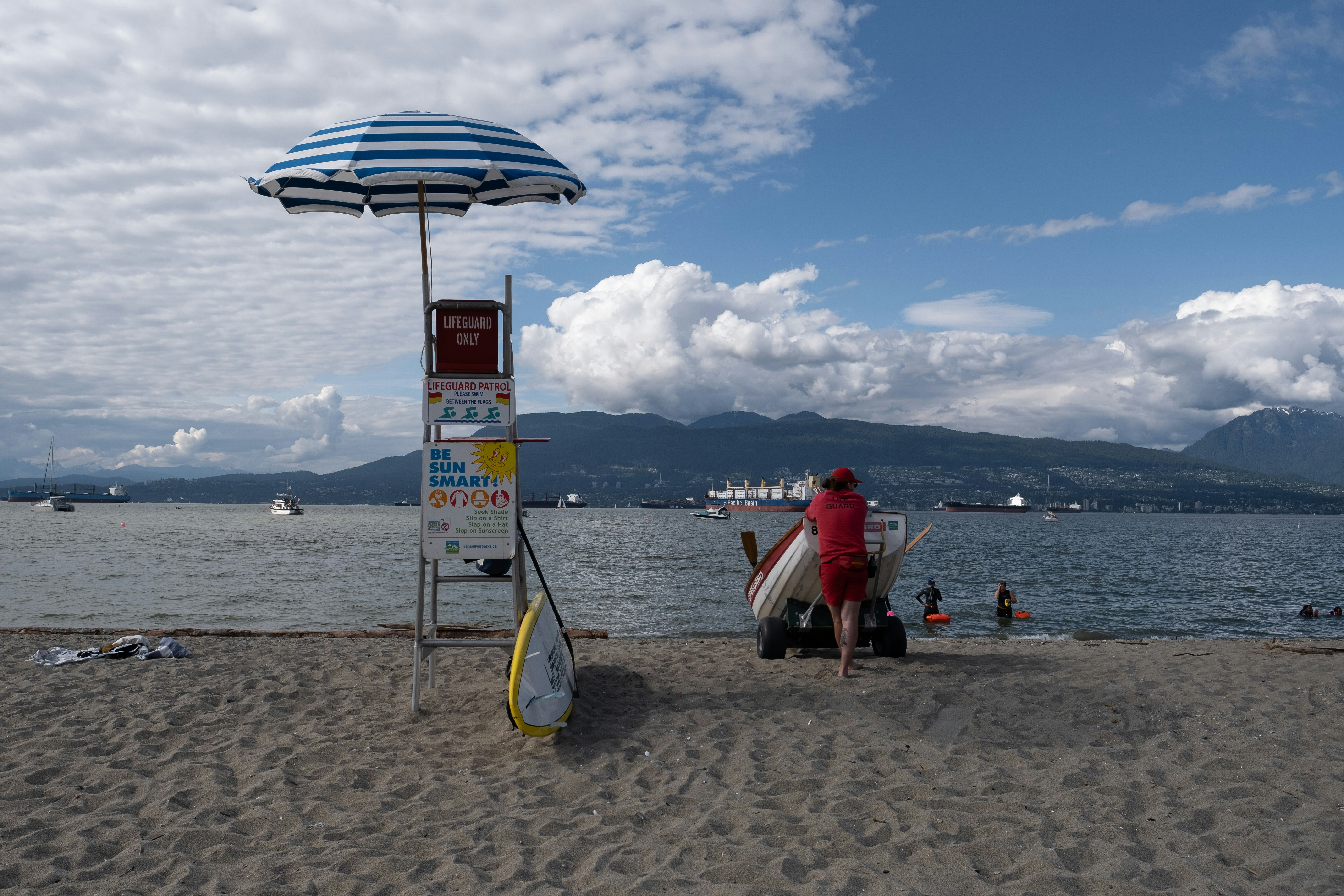 Lifeguard Stand and Beachgoers Under a Striped Canopy