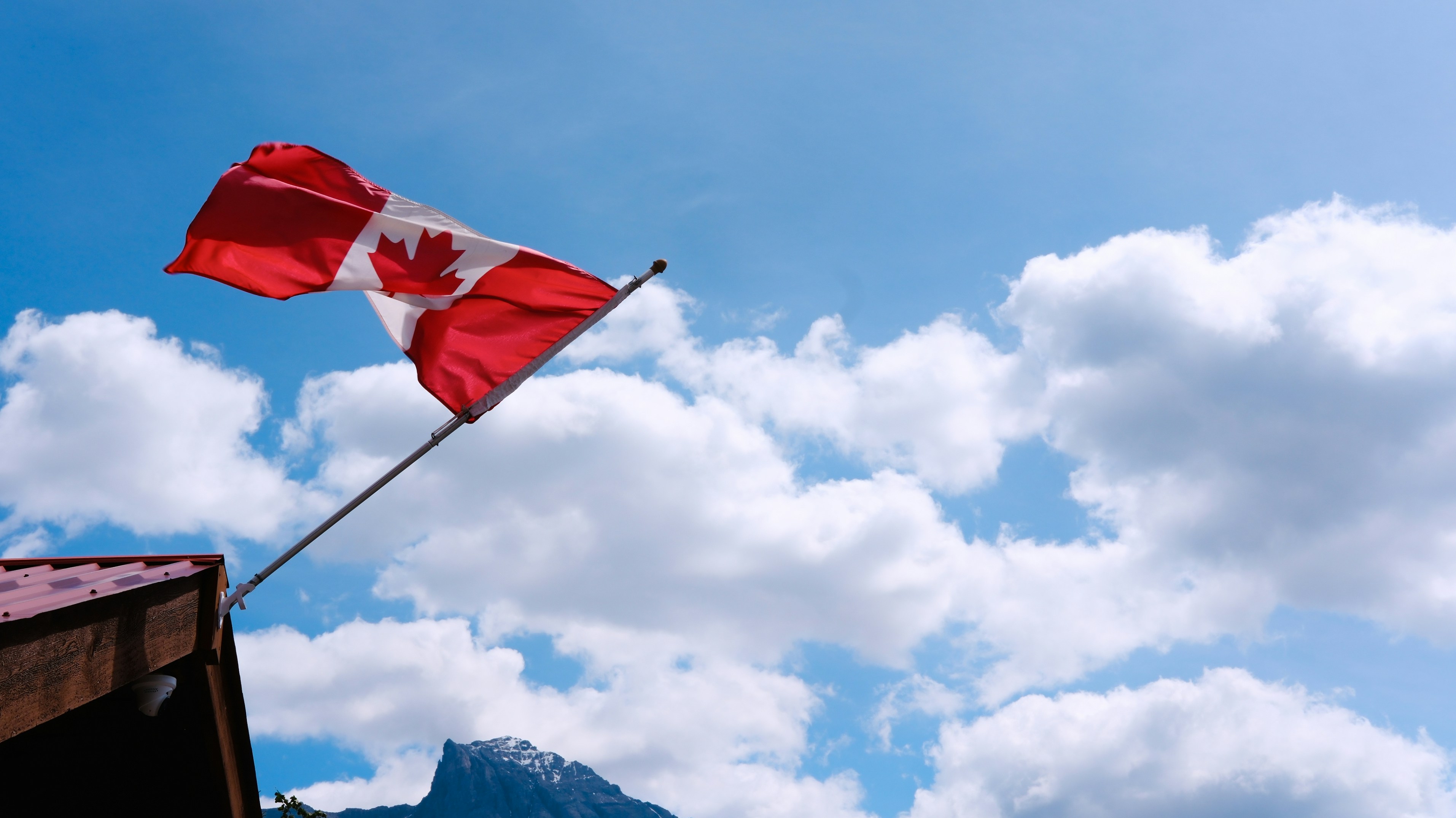 Flag Afloat: Canada’s Red and White Spear Amid Puffed Clouds