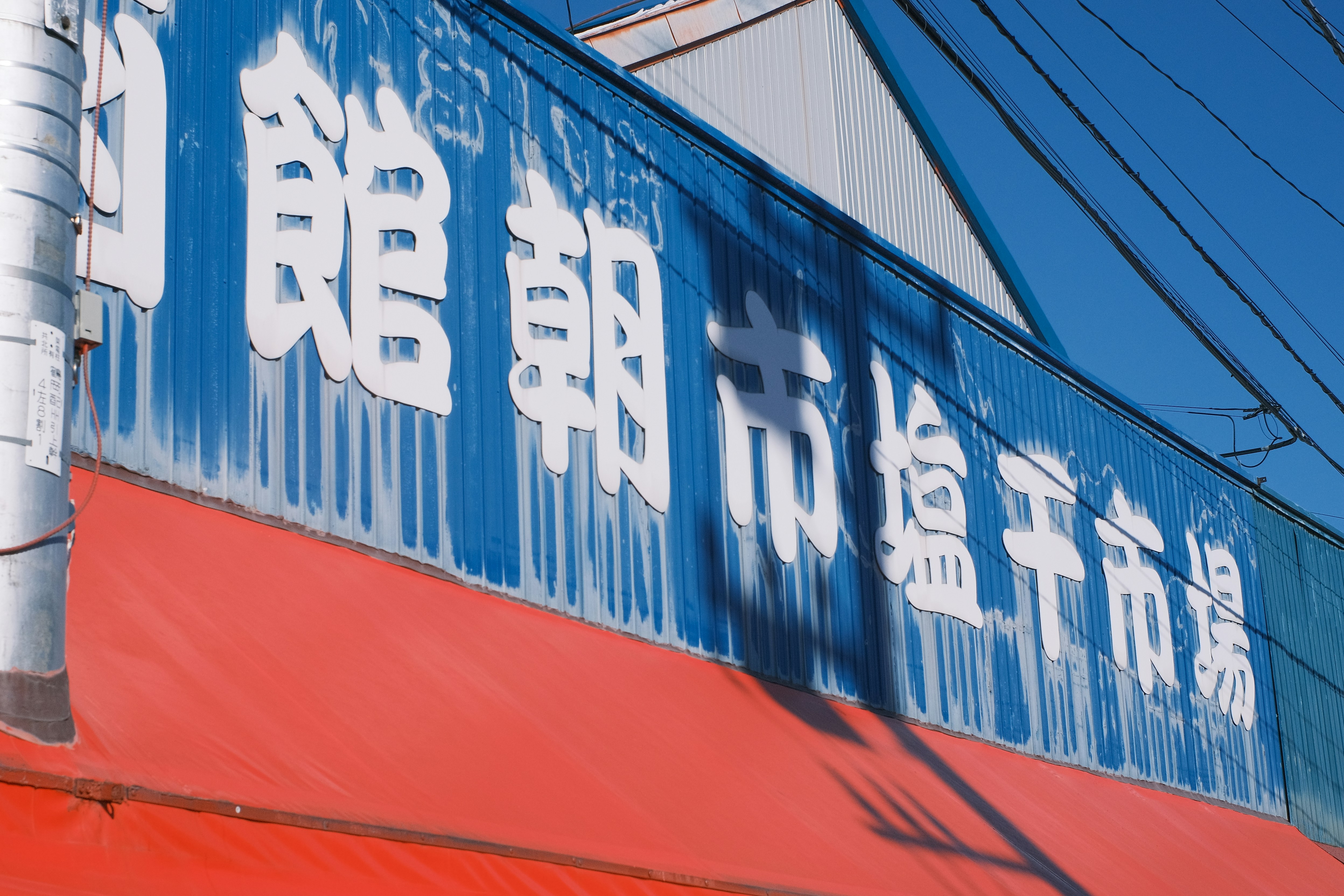 Blue Signboard Over Red Awning: Neon Blue Kanji Facade