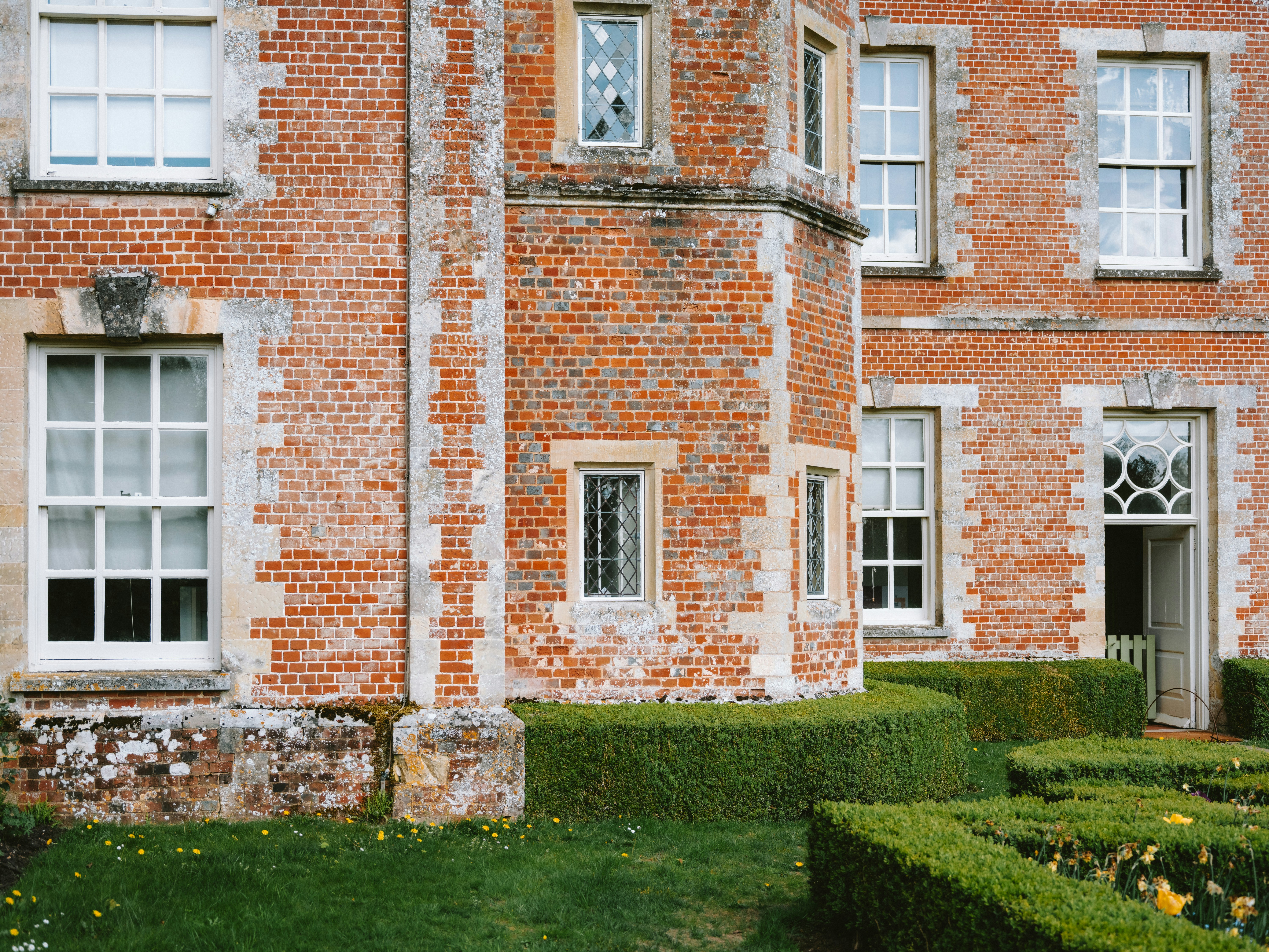 Brick Courtyard Wings: Neatly trimmed hedges framing an aged manor exterior