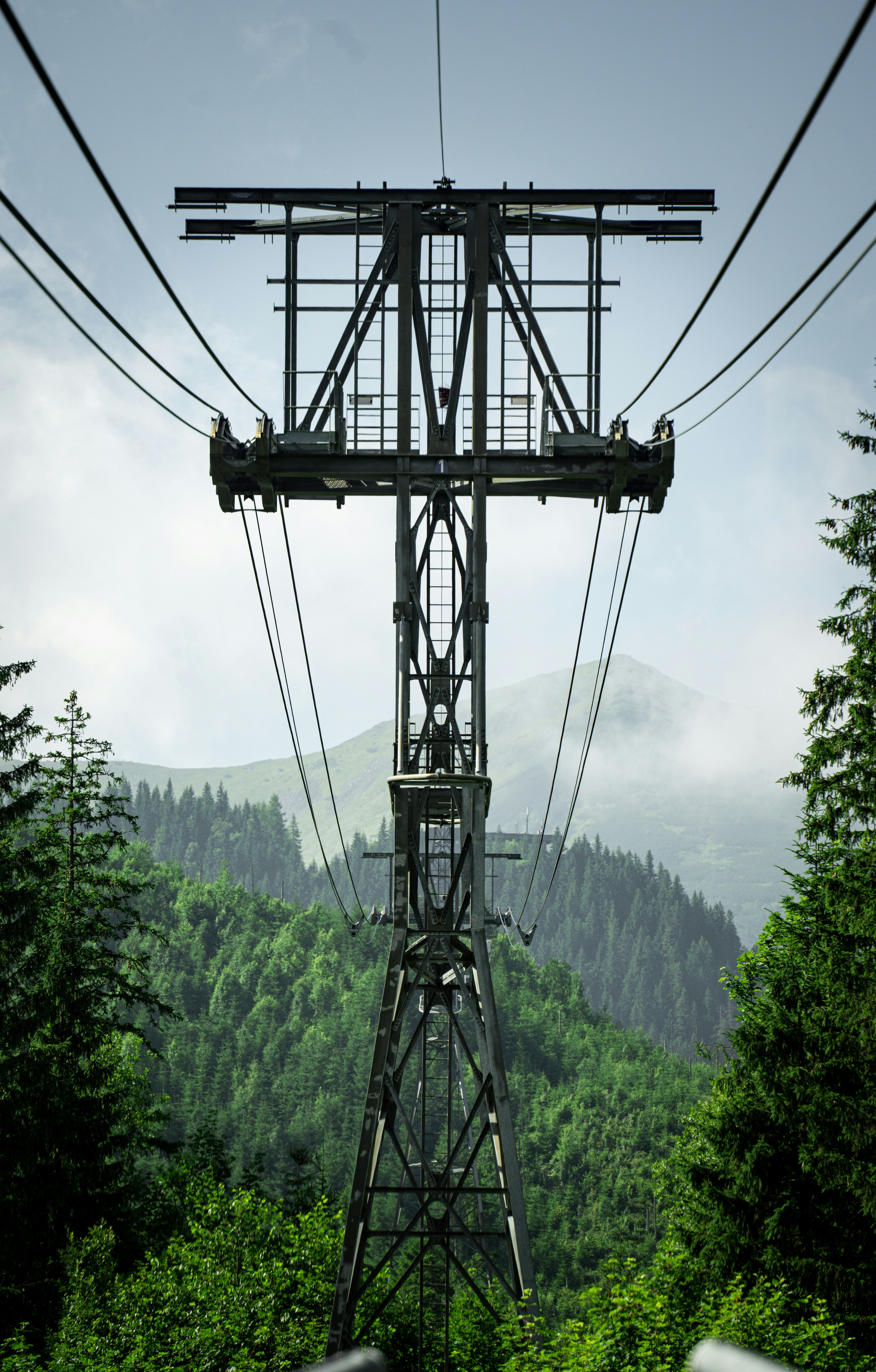Cable Car to the Clouds: A Towering Truss Amid Green Valleys
