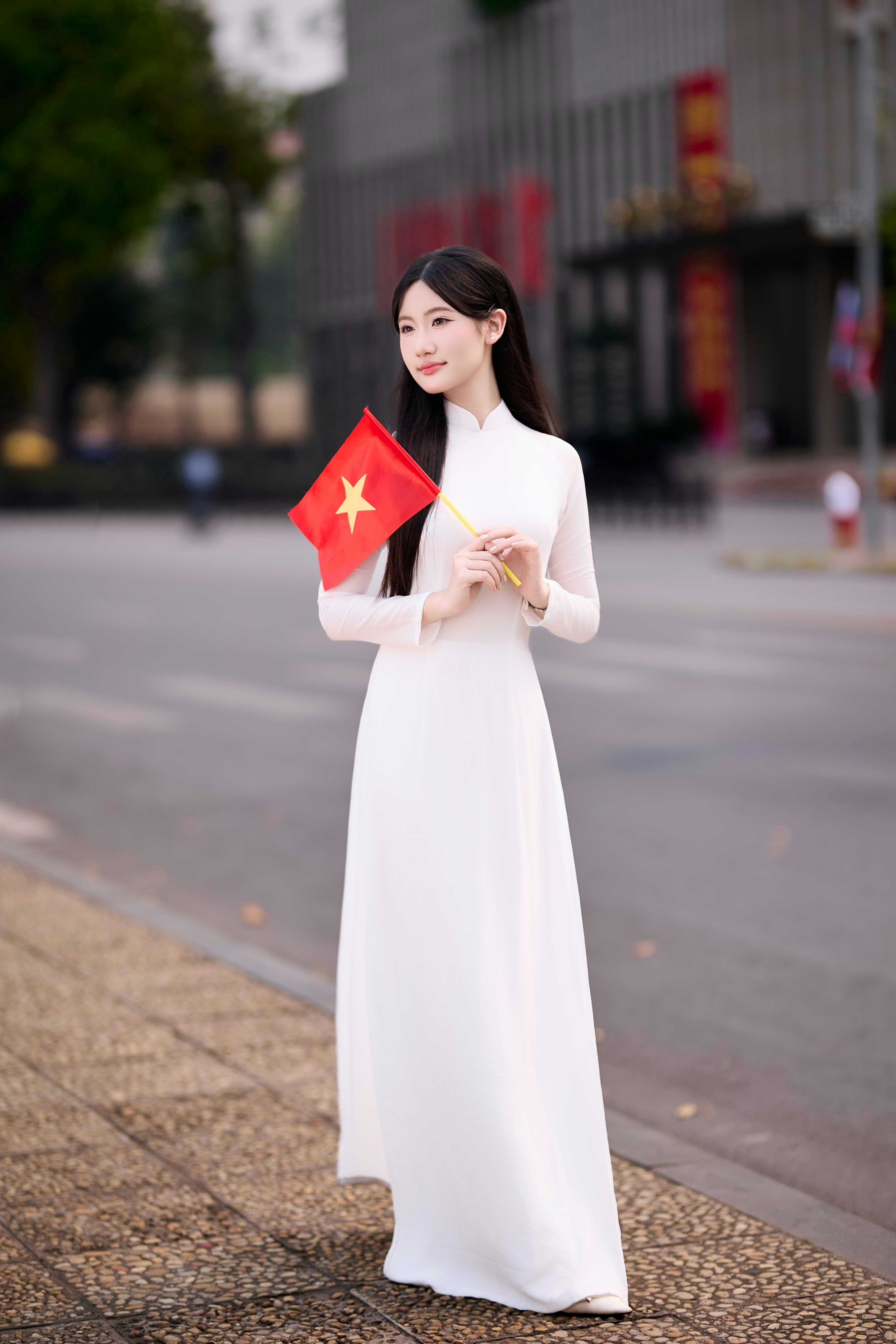A Quiet Portrait in a White Ao Dai with a Small Red Flag