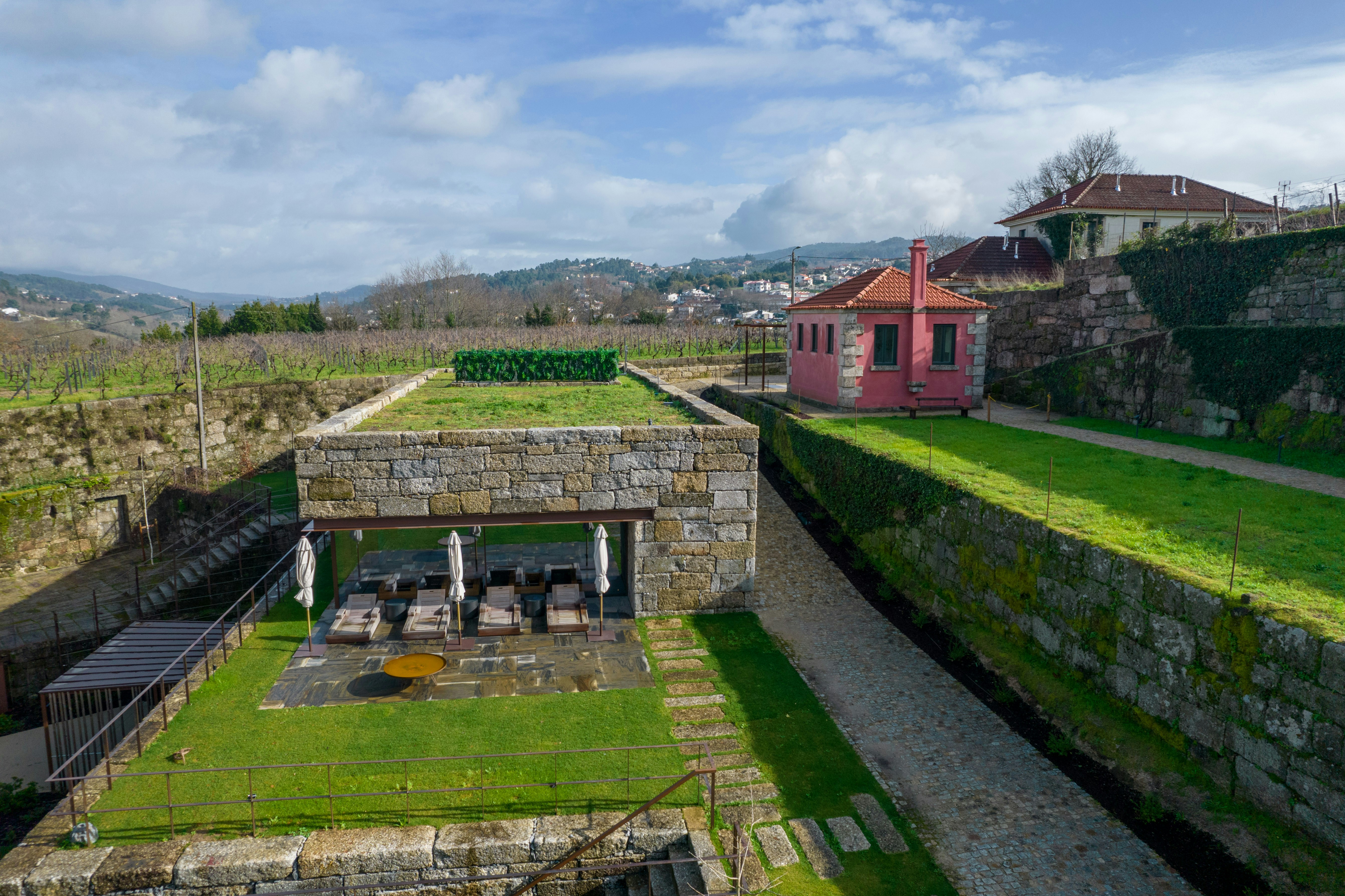 Terraced stone courtyard with pink pavilion overlooking a hillside village