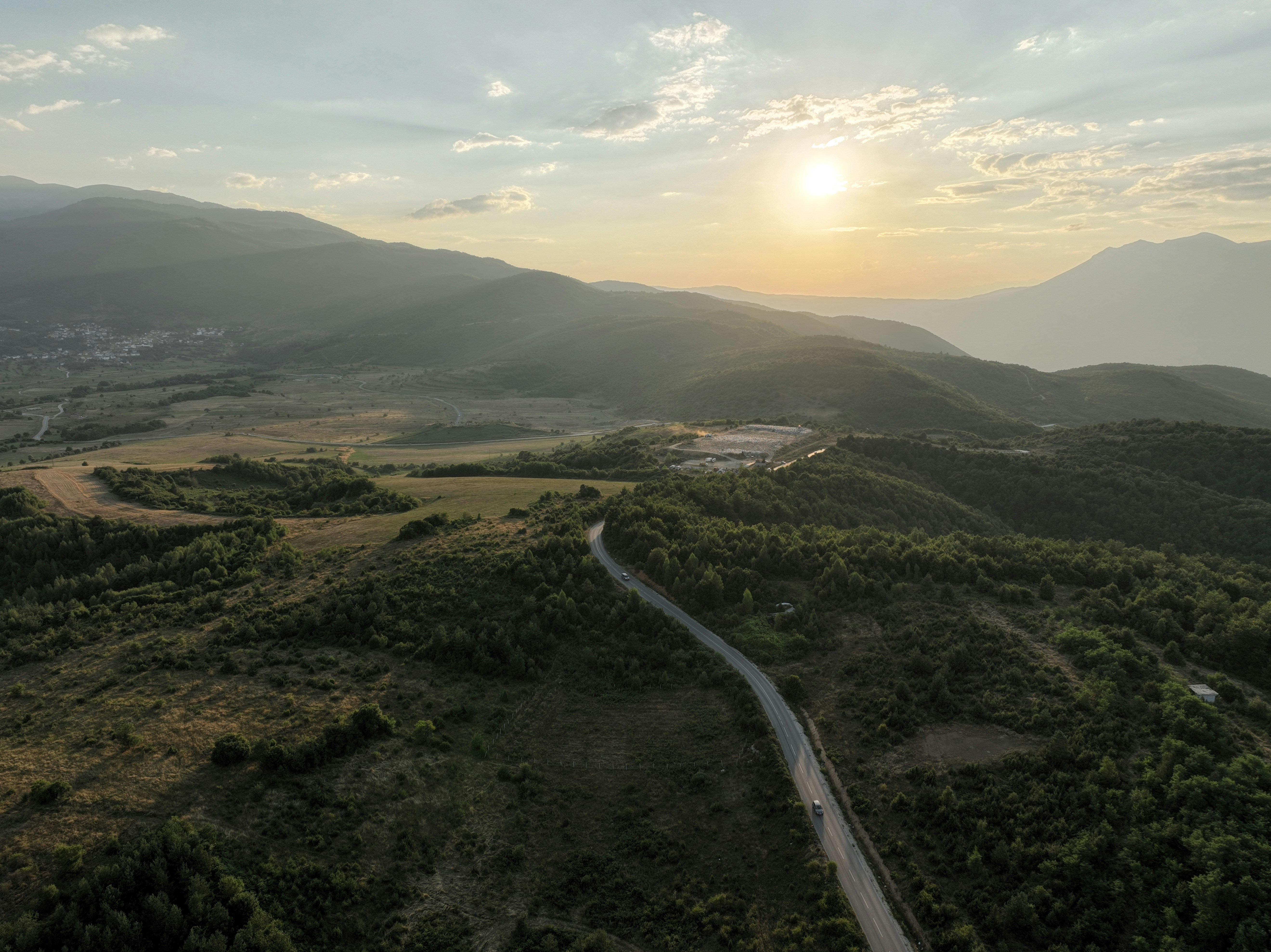 Sunlit Highway Through Rolling Hills at Dusk