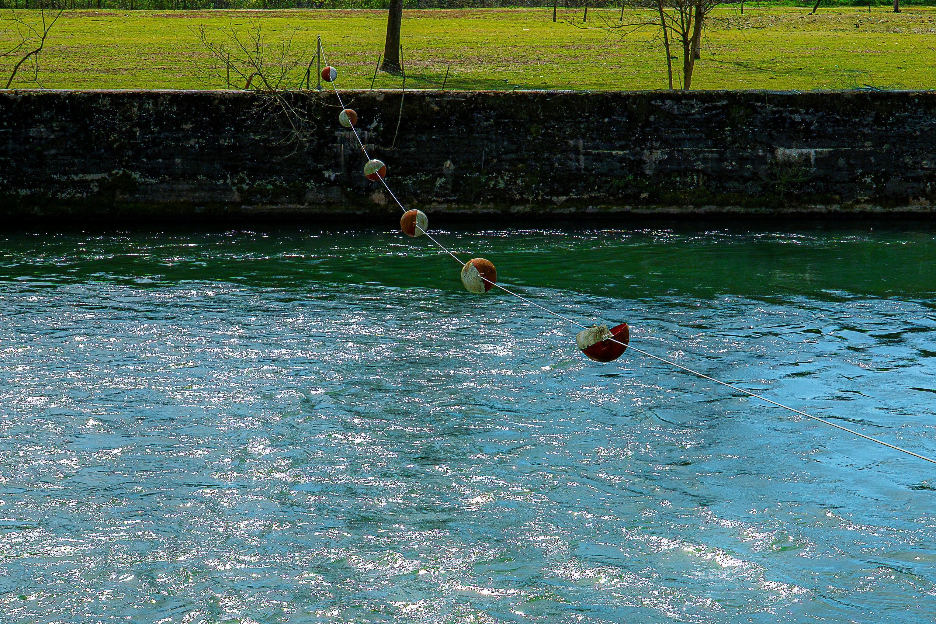 Buoyant Line: Buoys Drift Across a River Glass