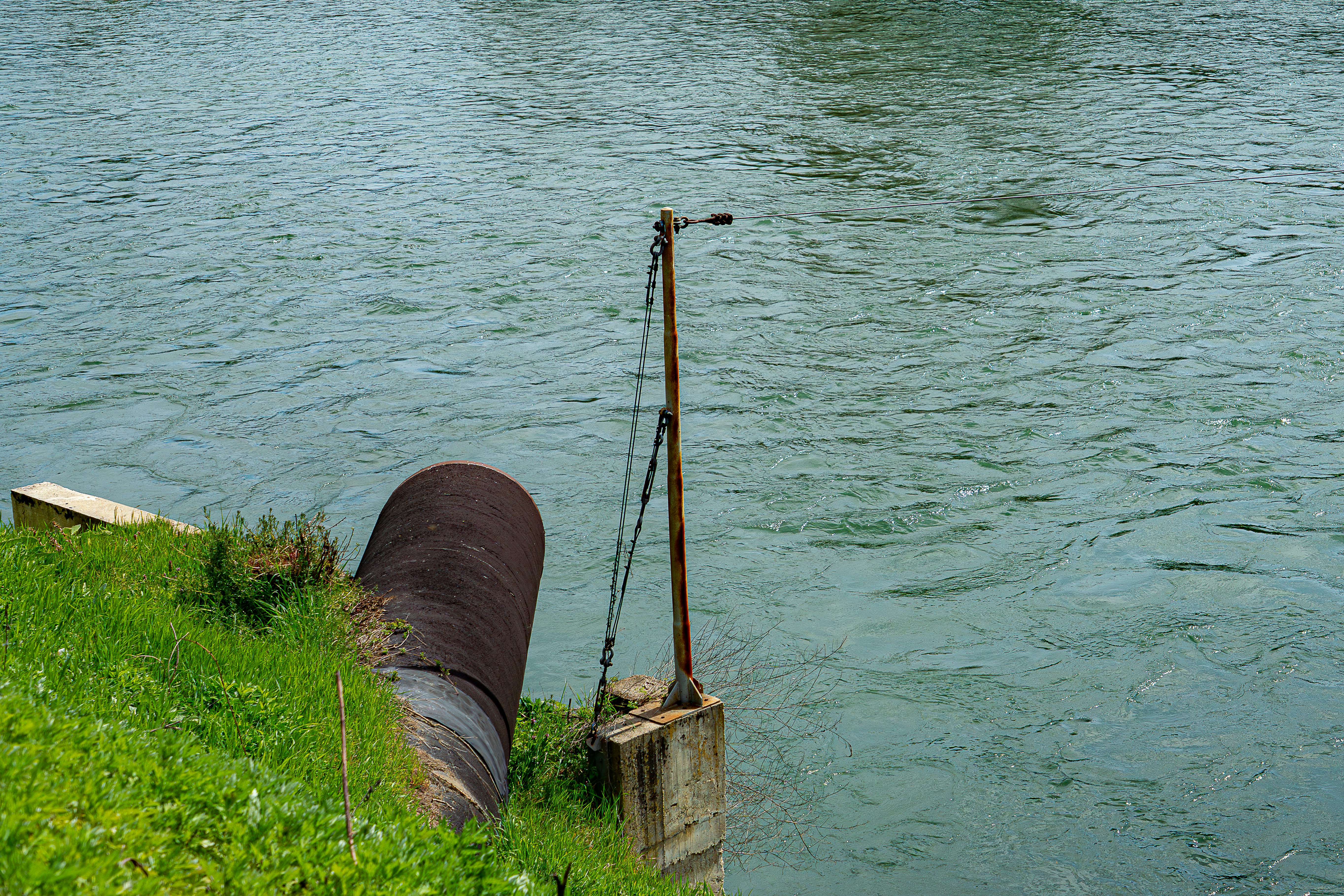 Industrial Pipe Run Brushing Against a Quiet Riverside