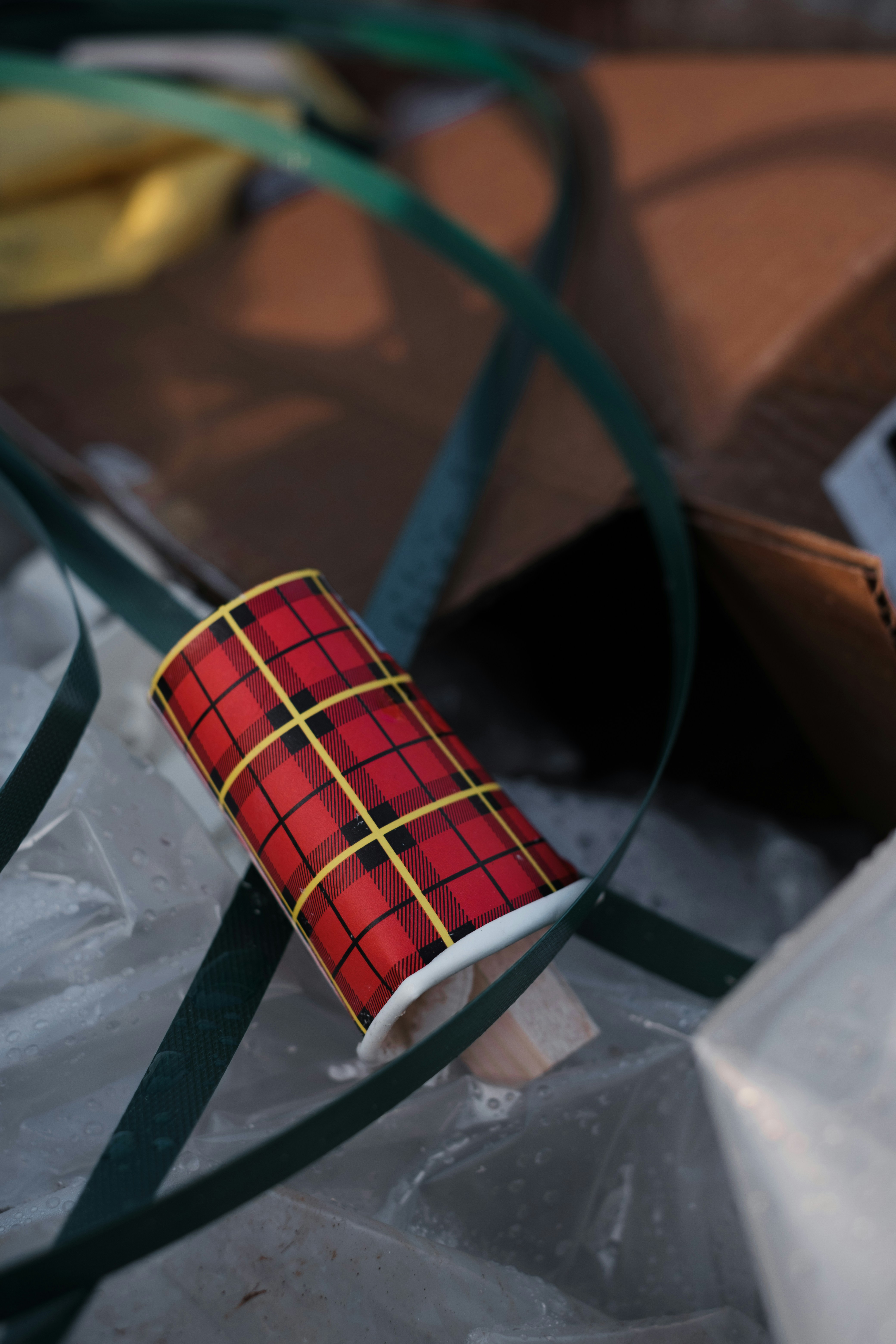 Close-up of a red plaid party popper amidst garbage and cords