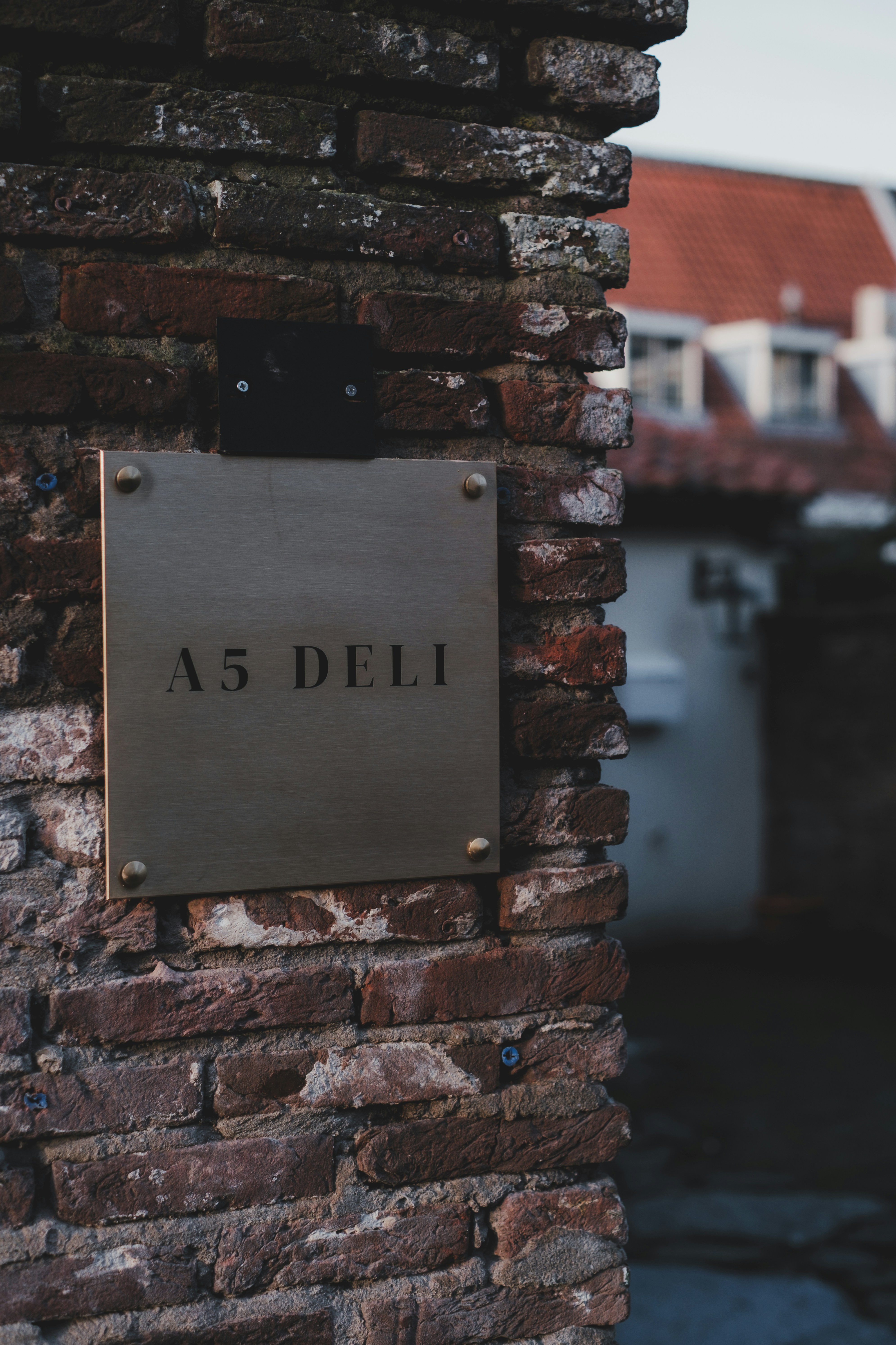 Metal Plaque on Weathered Brick Wall—A5 Deli