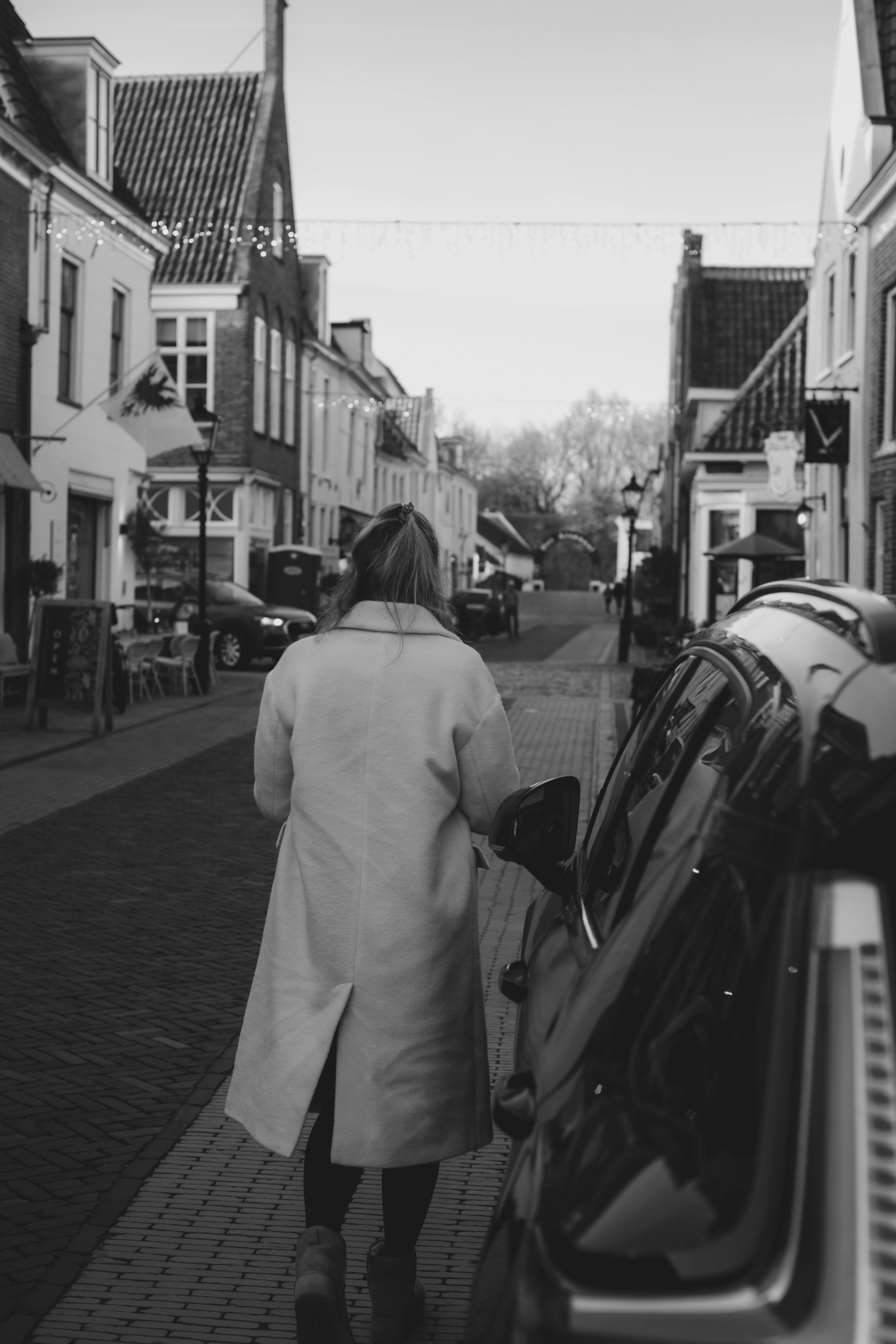 Cozy Street Portrait: A Woman in a Long Coat Walking Down a European Lane