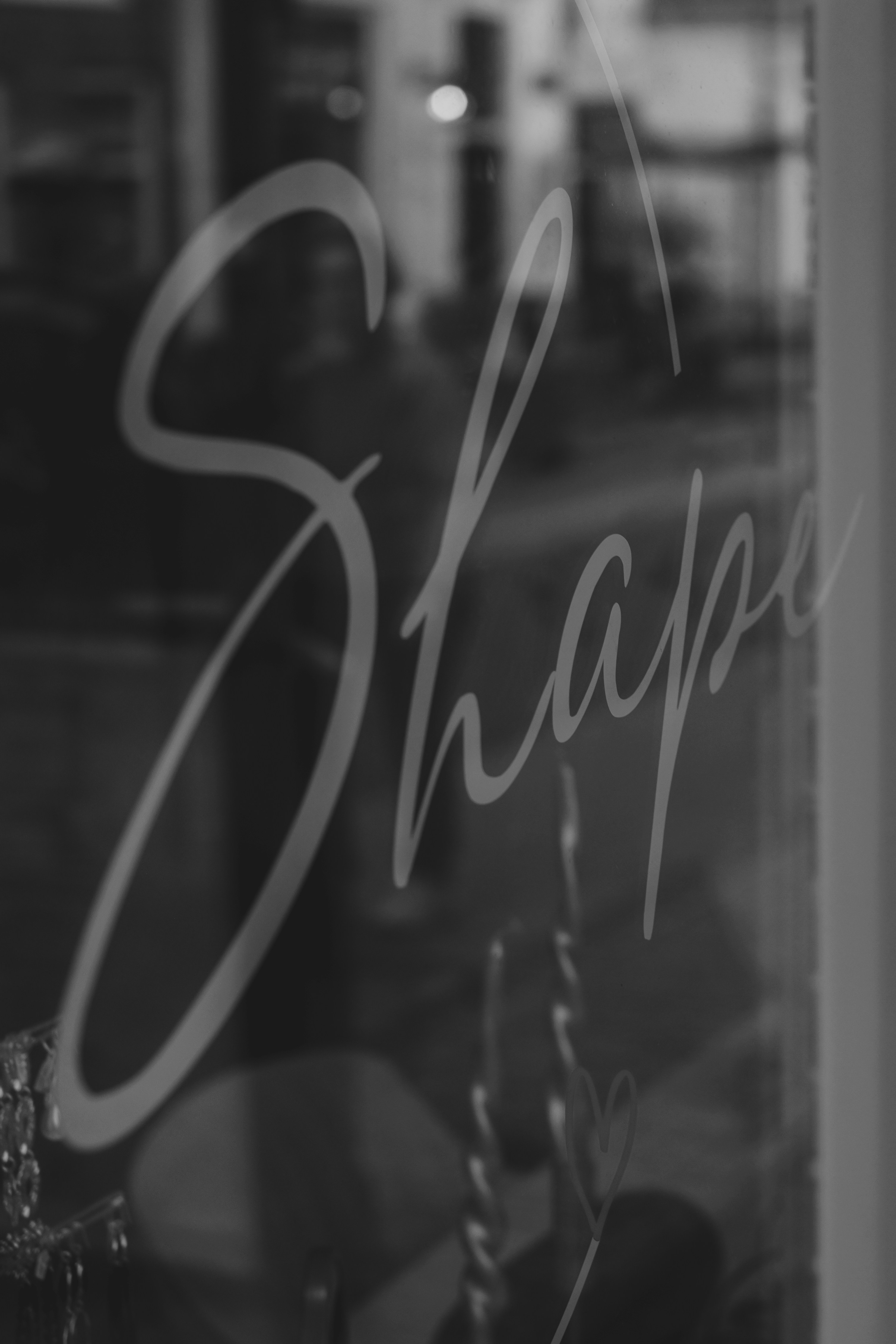 Glassy storefront script: SHAPED lettering fading into a reflective street scene