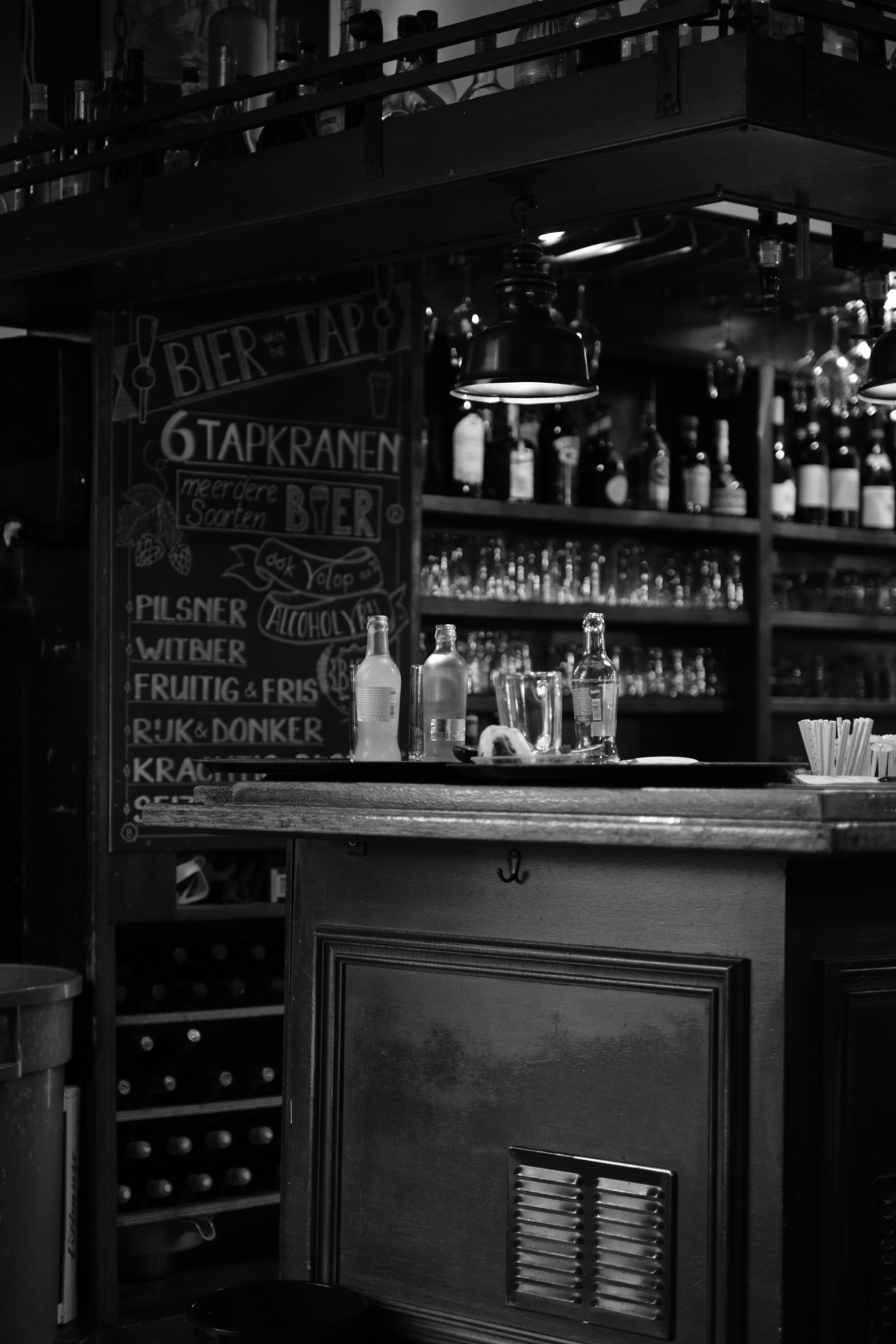Backbar Quietly Lit: Bottles, Chalkboard, and a Centered Counter
