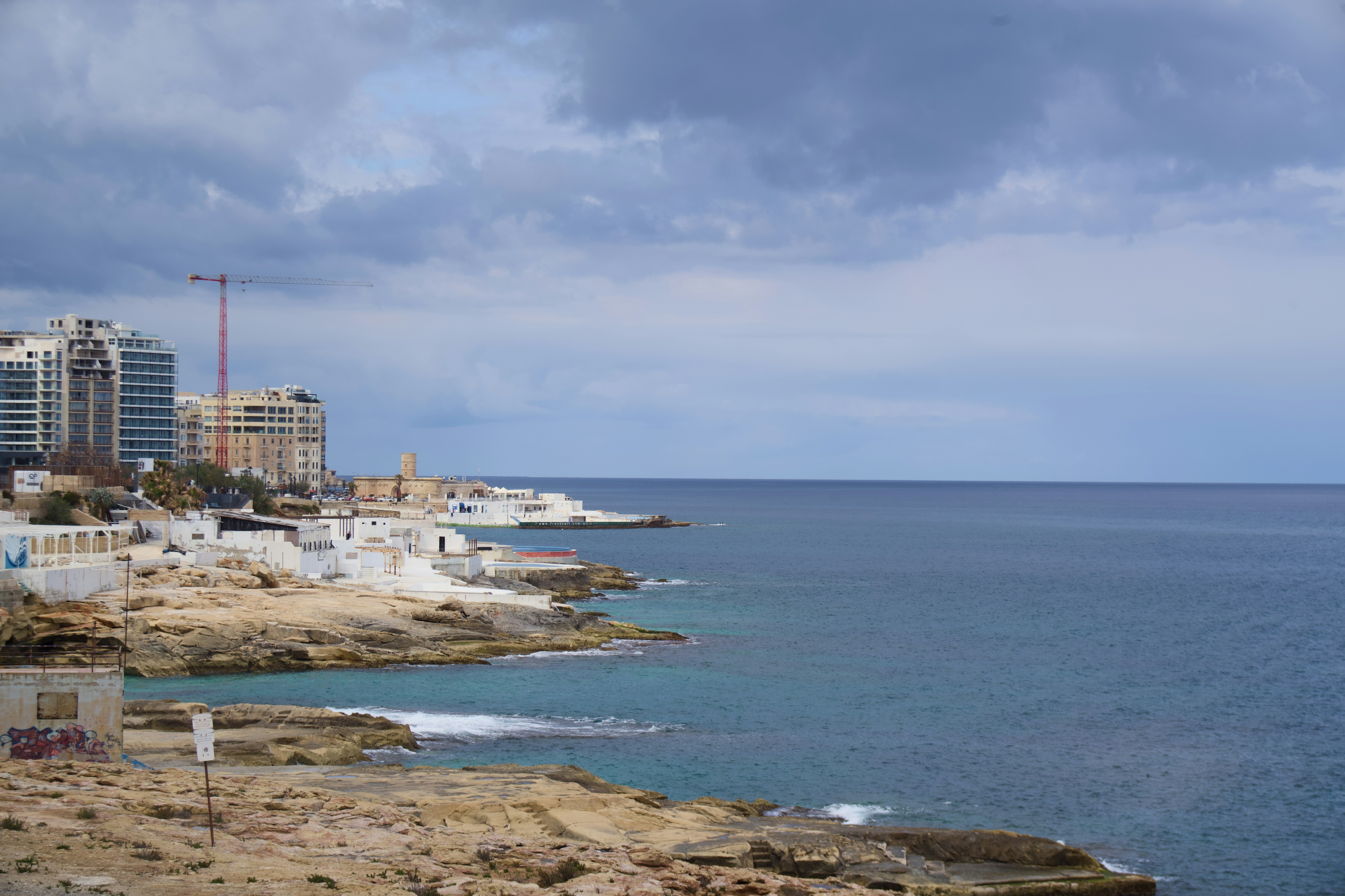 Coastal Cliffs and Quiet Harbor Under a Brushed Sky