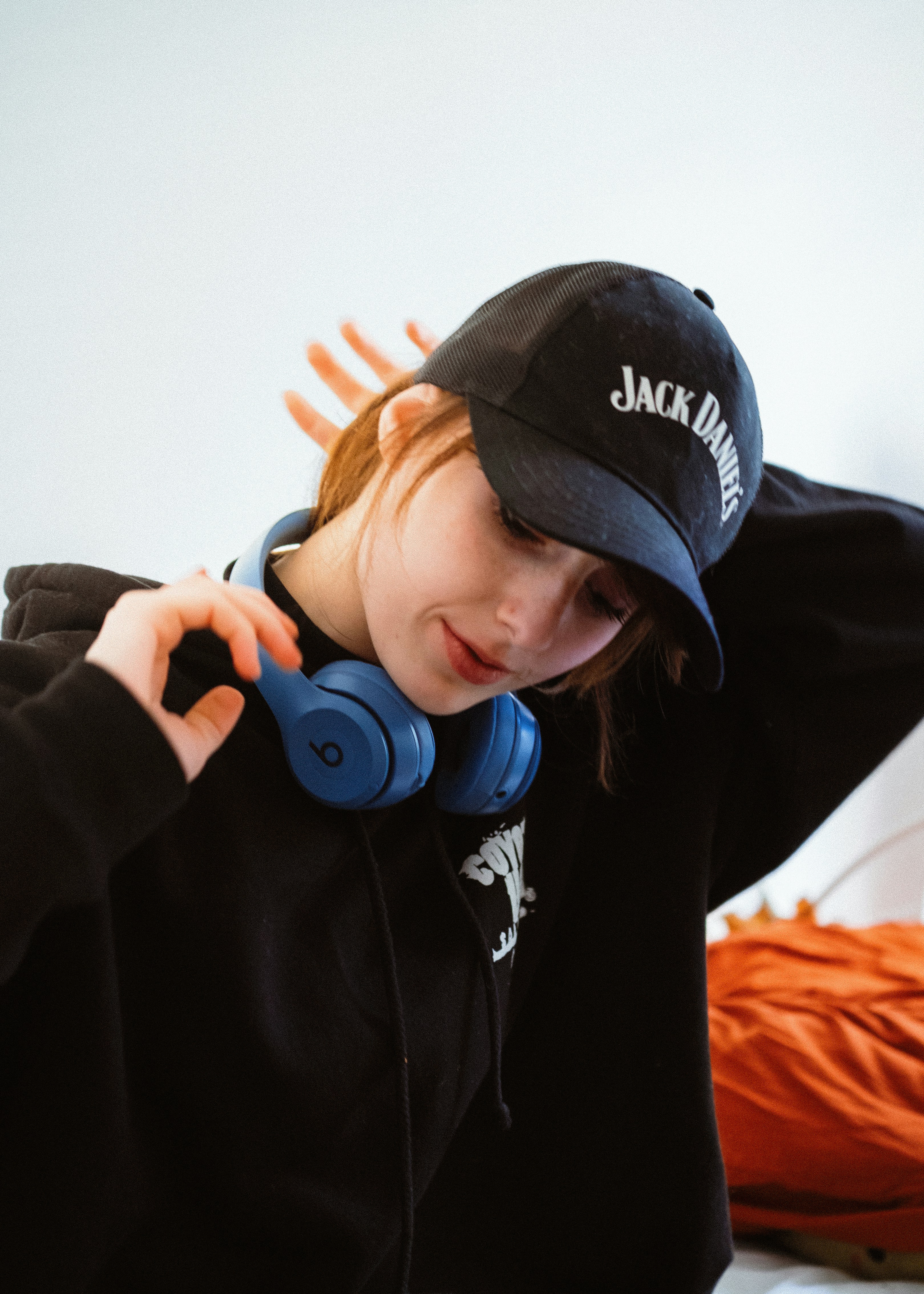 Blue headphones and curious gaze under a Jack Daniel’s cap