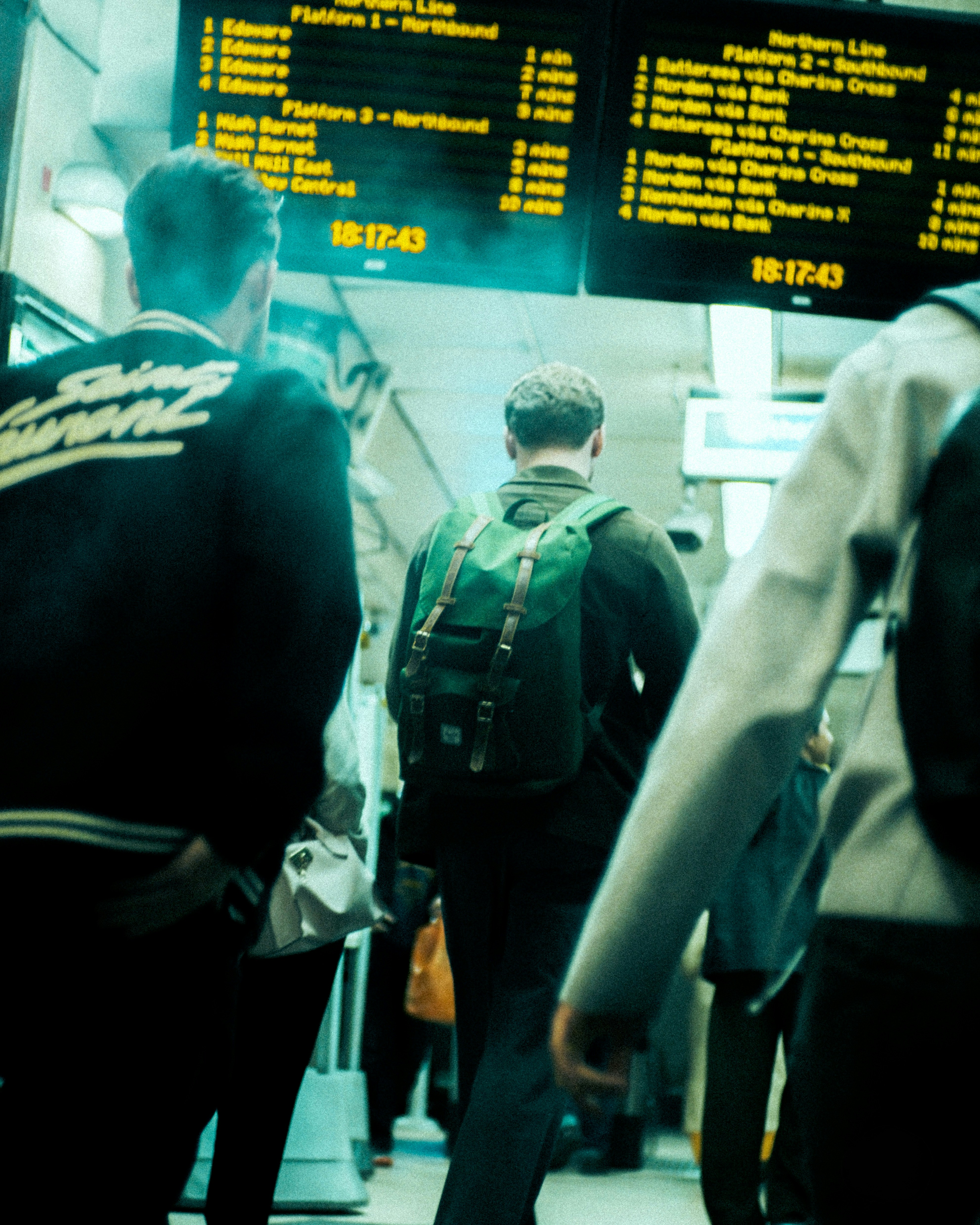 Backlit commuters in a neon-lit concourse beneath a departure board