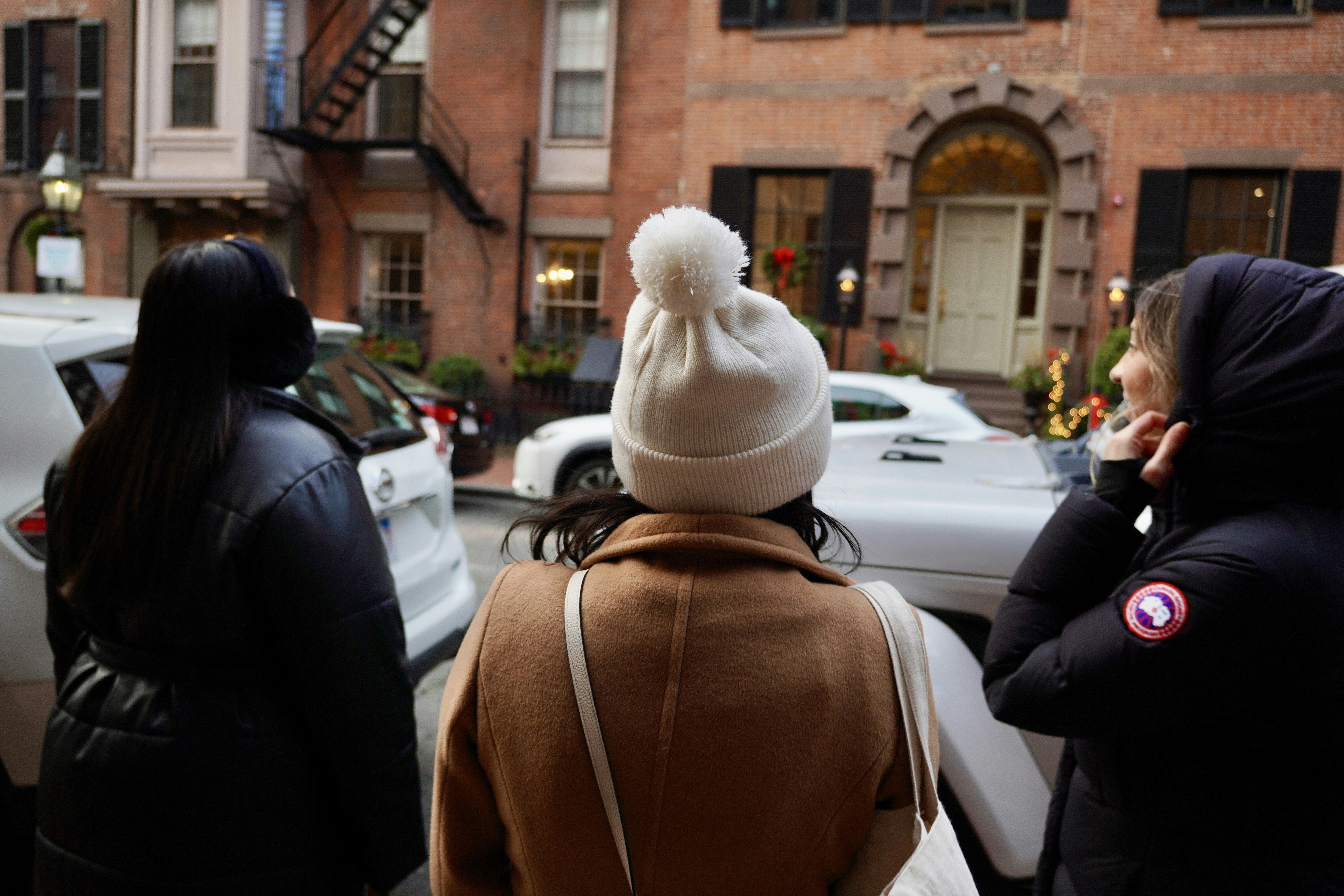 Winter street reunion: three figures framed against brick townhouses