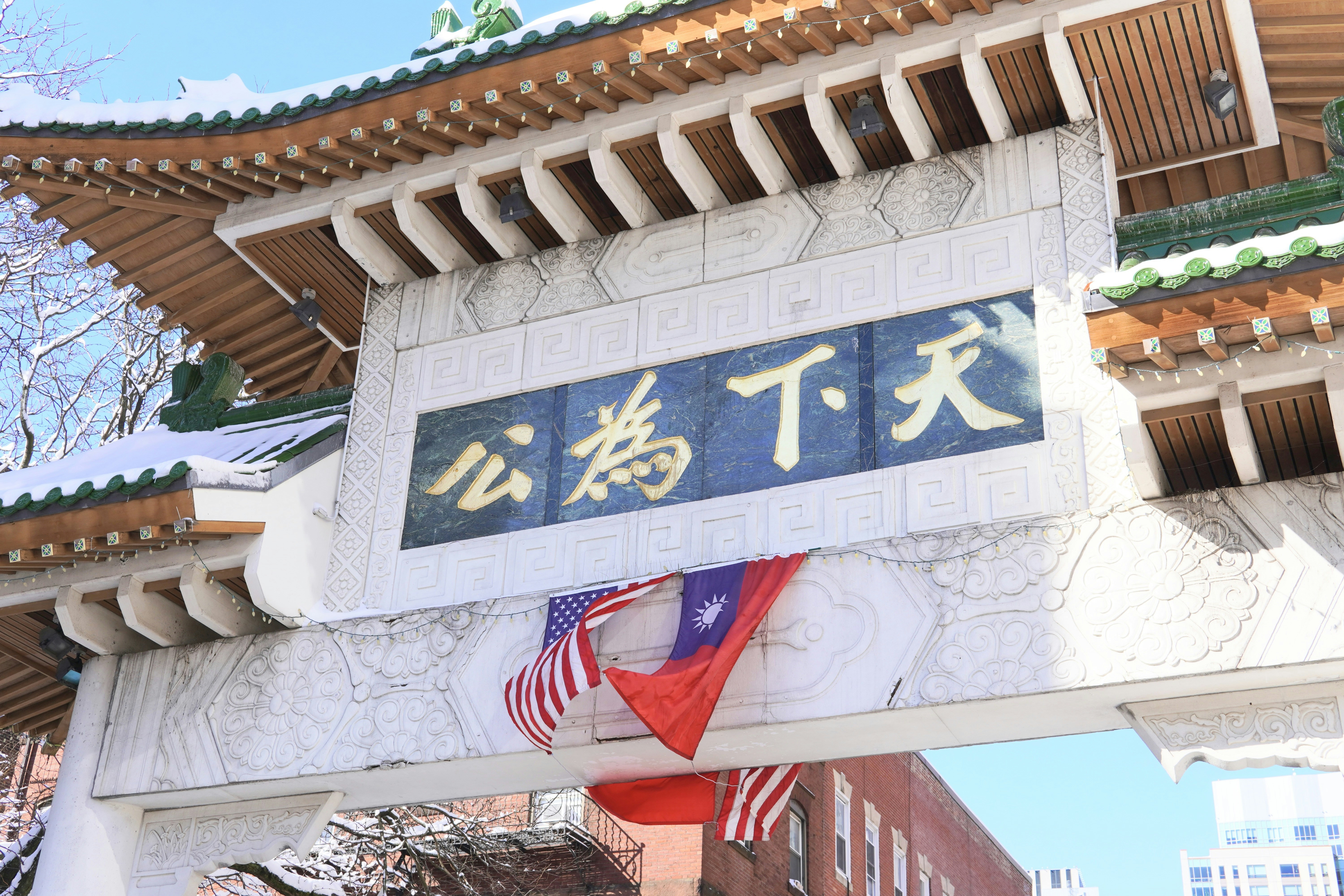 Gateway to Harmony: A Chinese Arch Framed by Blue Sky and Flags