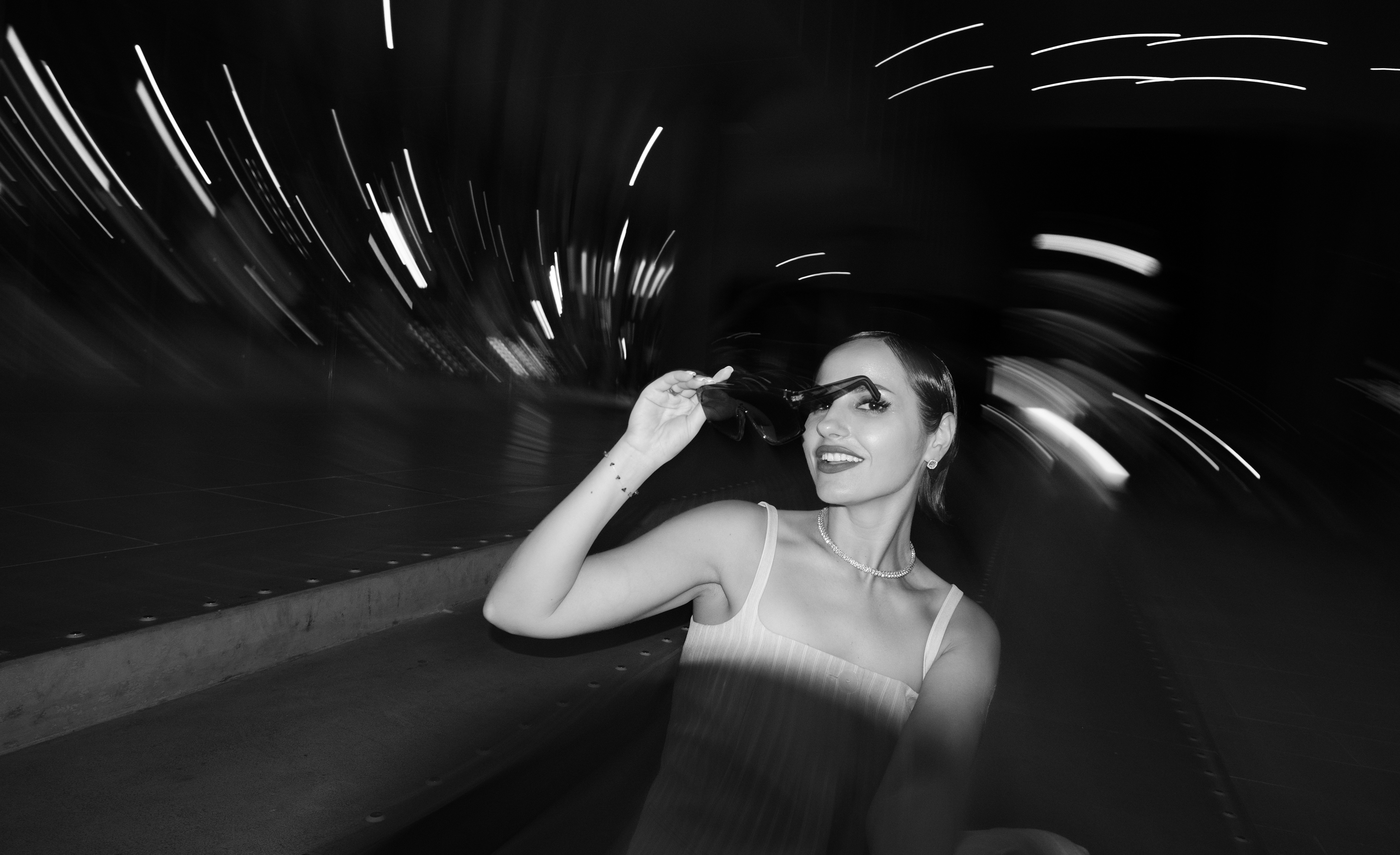 Night Drive: A City Streaks Past as She Smiles Into the Lens