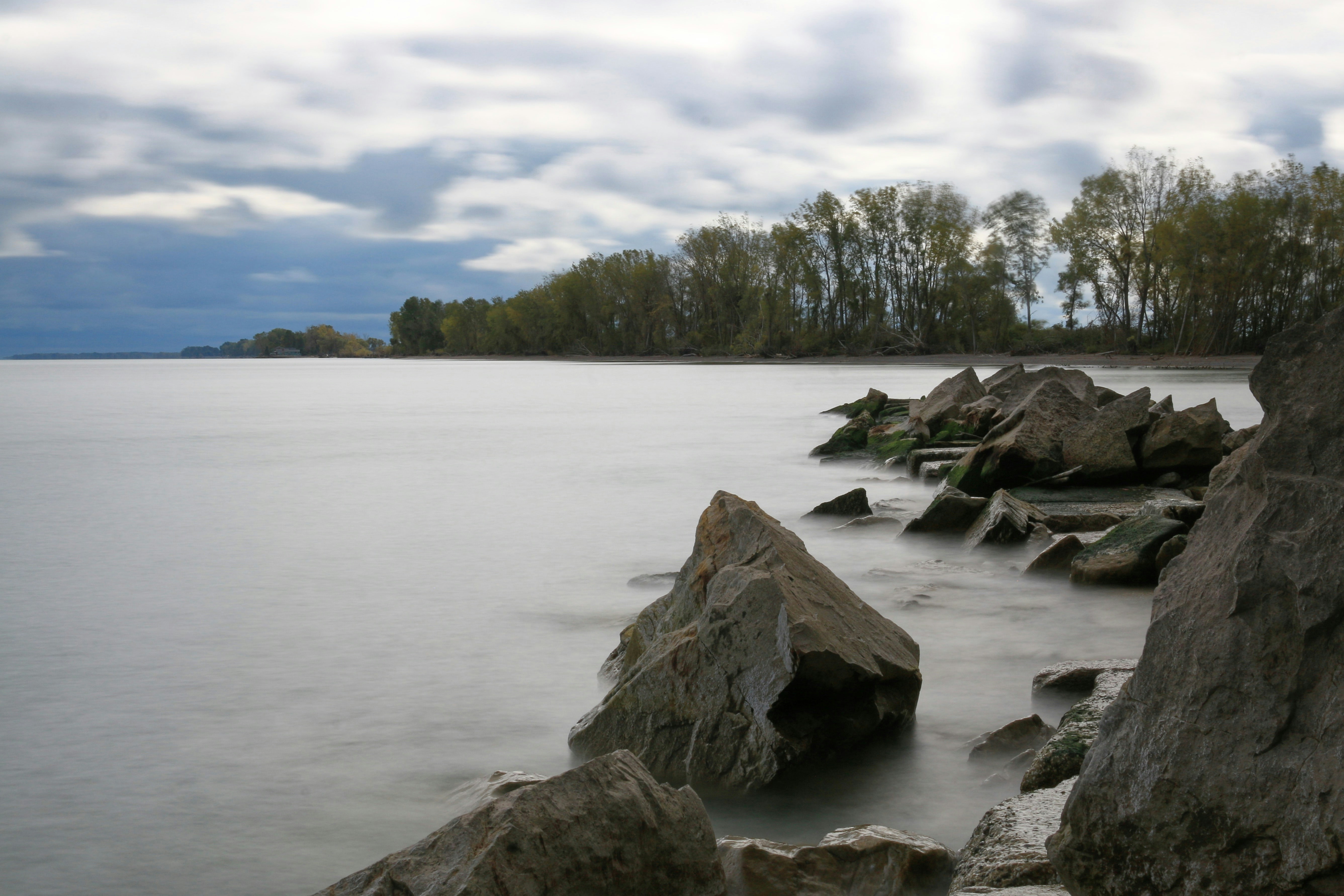 Rugged shoreline receding into a calm horizon under a brooding sky