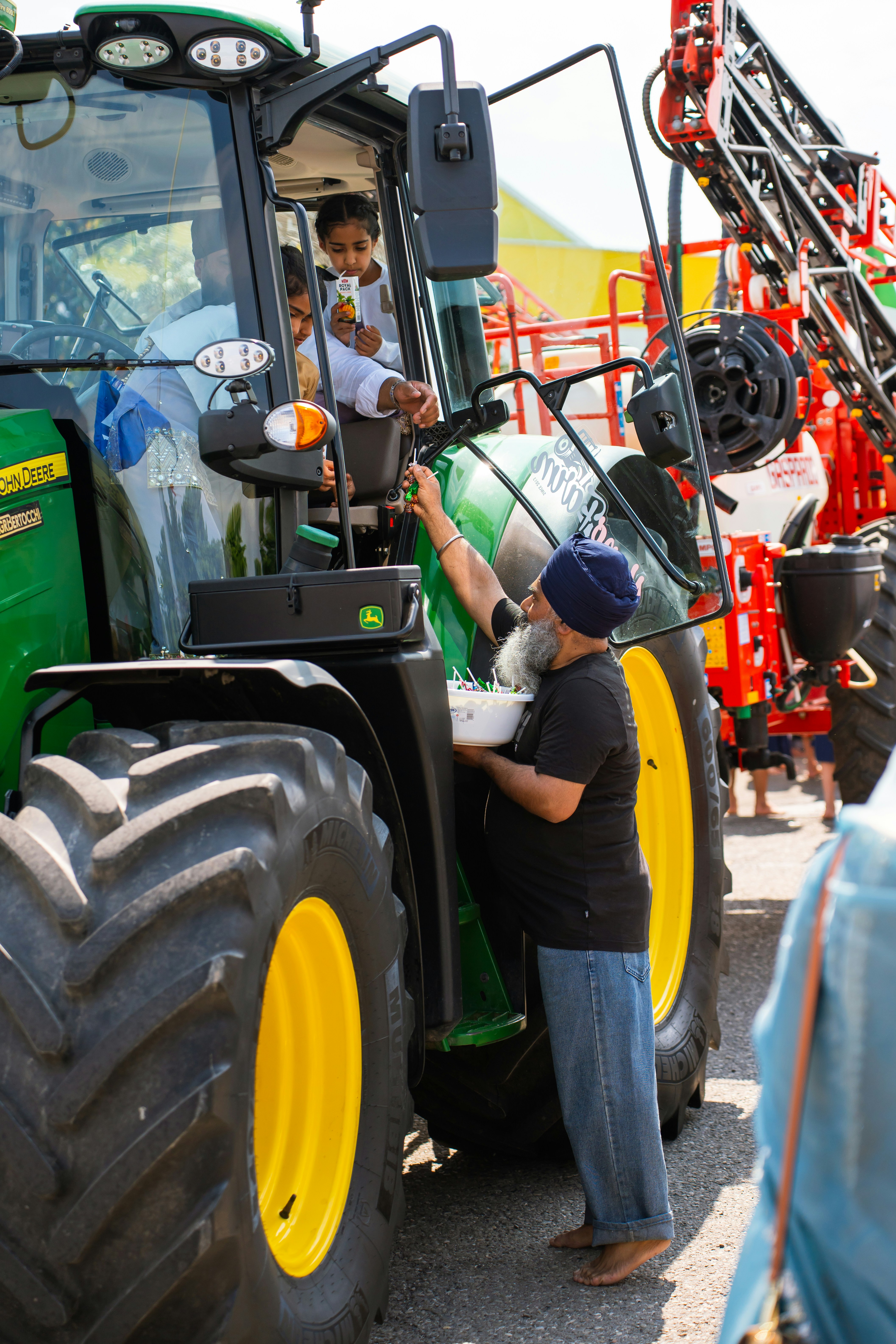 Harvest of Shared Smiles: A Grandchild Sits in Front of a Tractor as Grandpa Hands Over a Snack