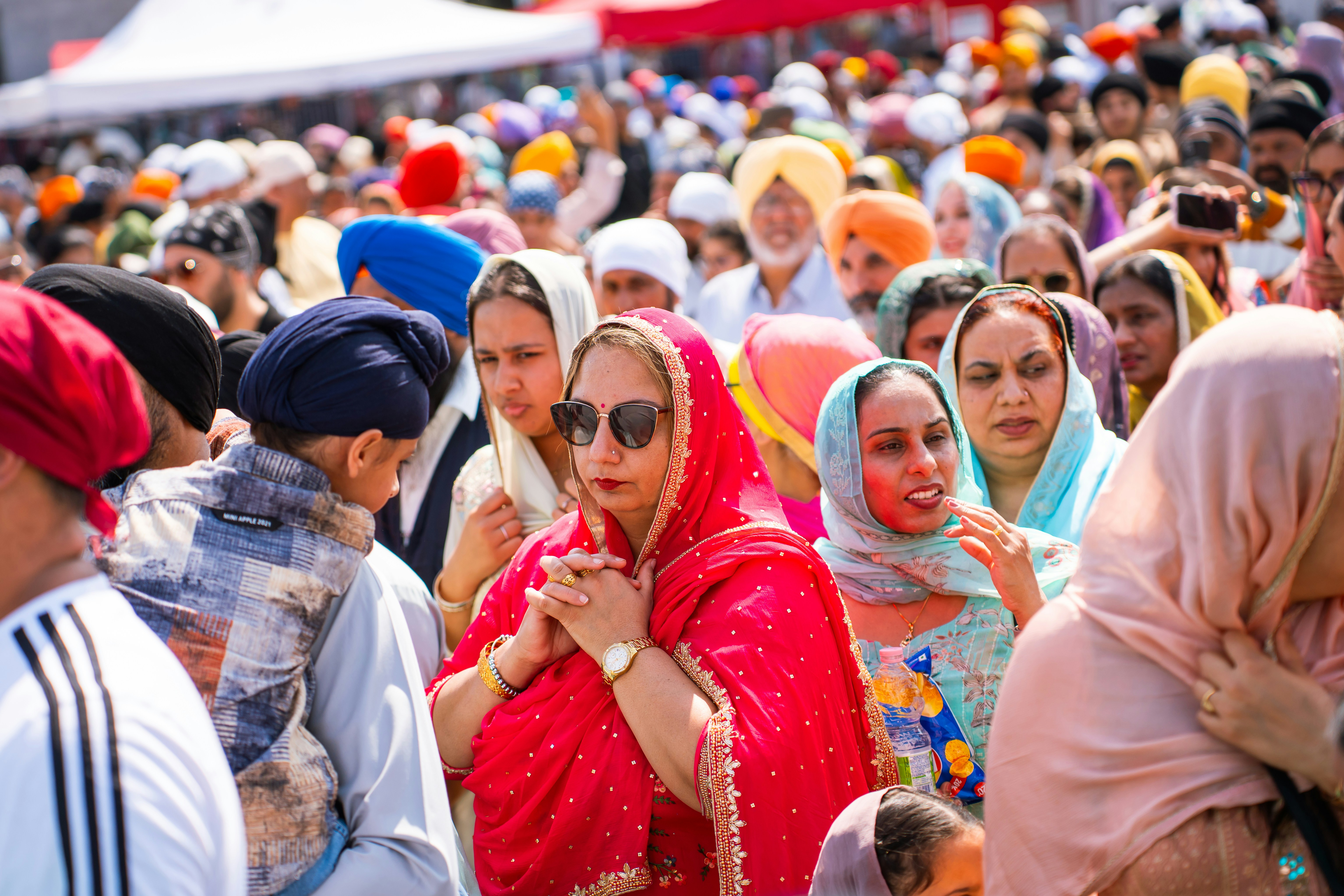 Colorful Crowd at a Indian Festival: Veiled Faces and Sunglasses Amidst Bright Fabrics