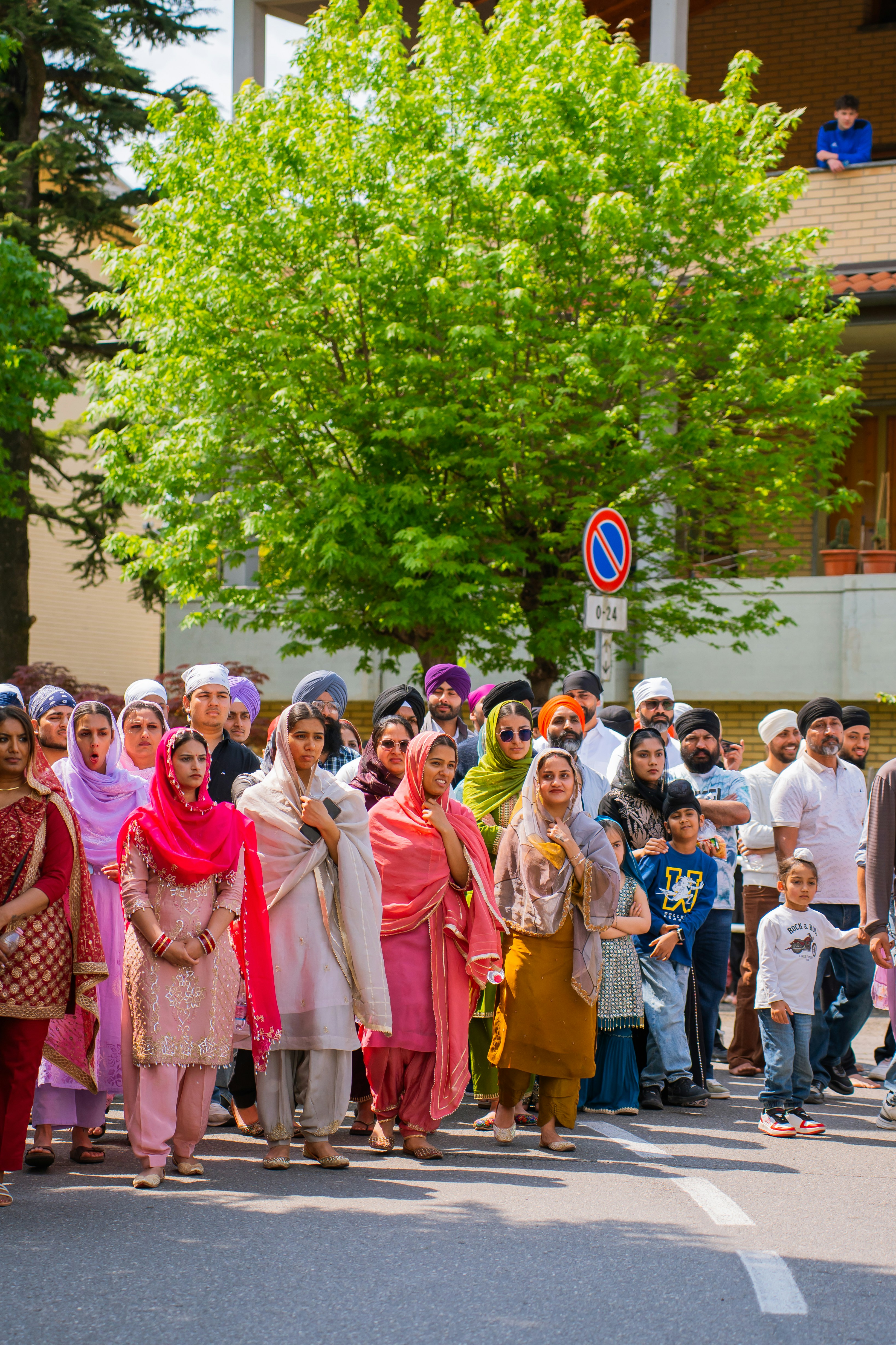 Gathered on the Street: A Colorful Crowd in Traditional Attire Beneath Bright Green Canopy
