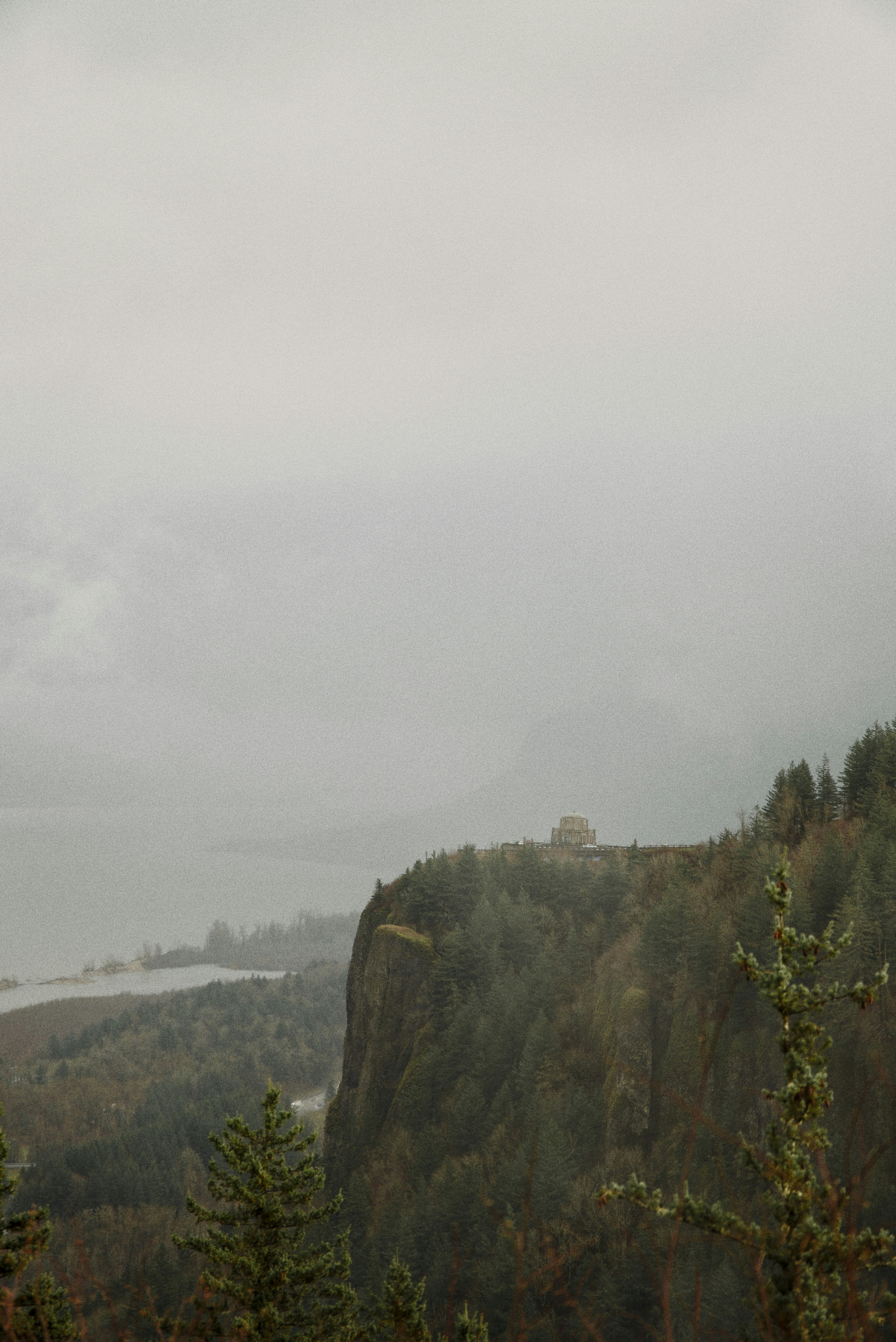 Cliffside Vista with a Distant Structure Amid Mist