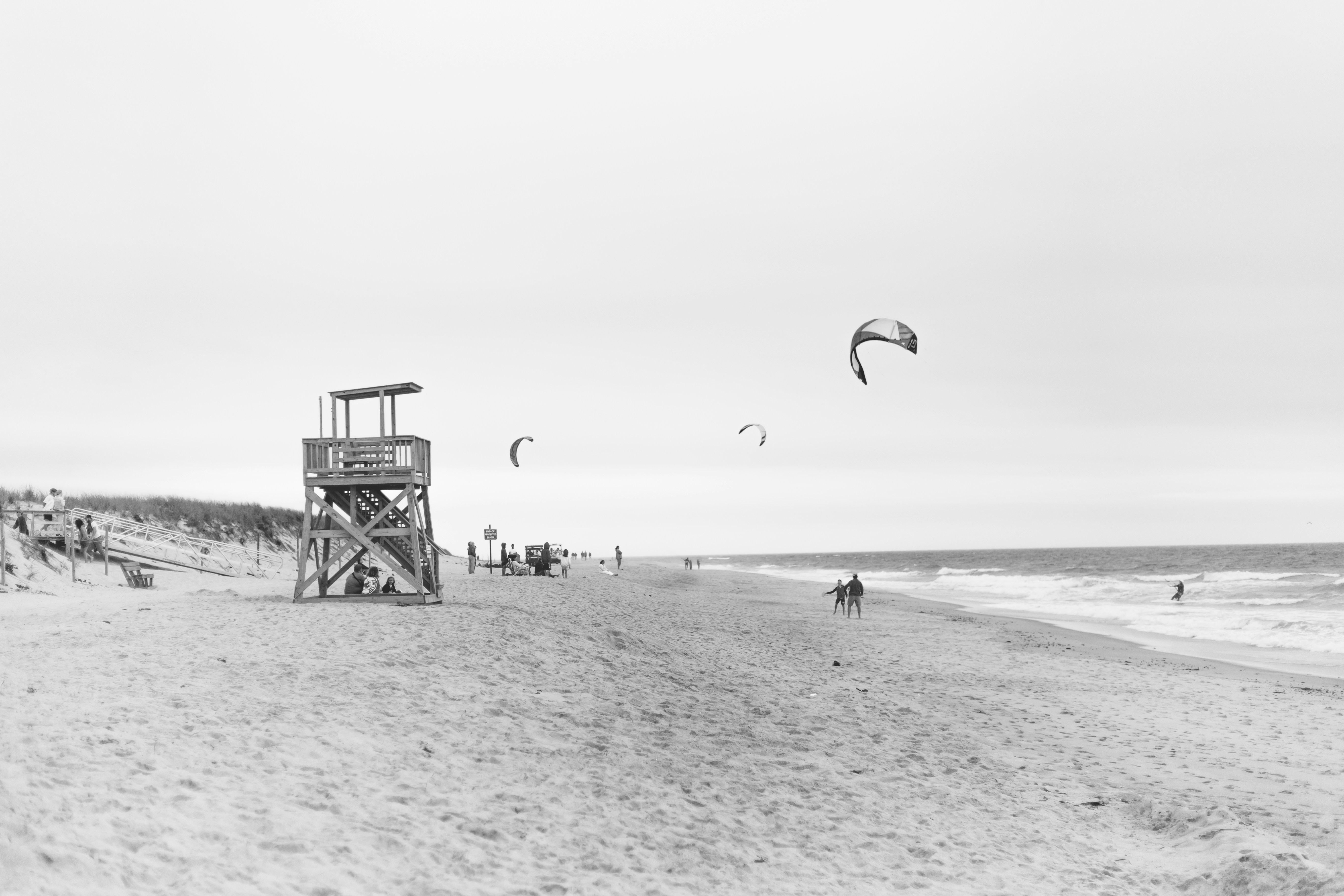 Shoreline Silhouettes: Lifeguard Tower and Kite Surfers at Dusk on a Quiet Beach