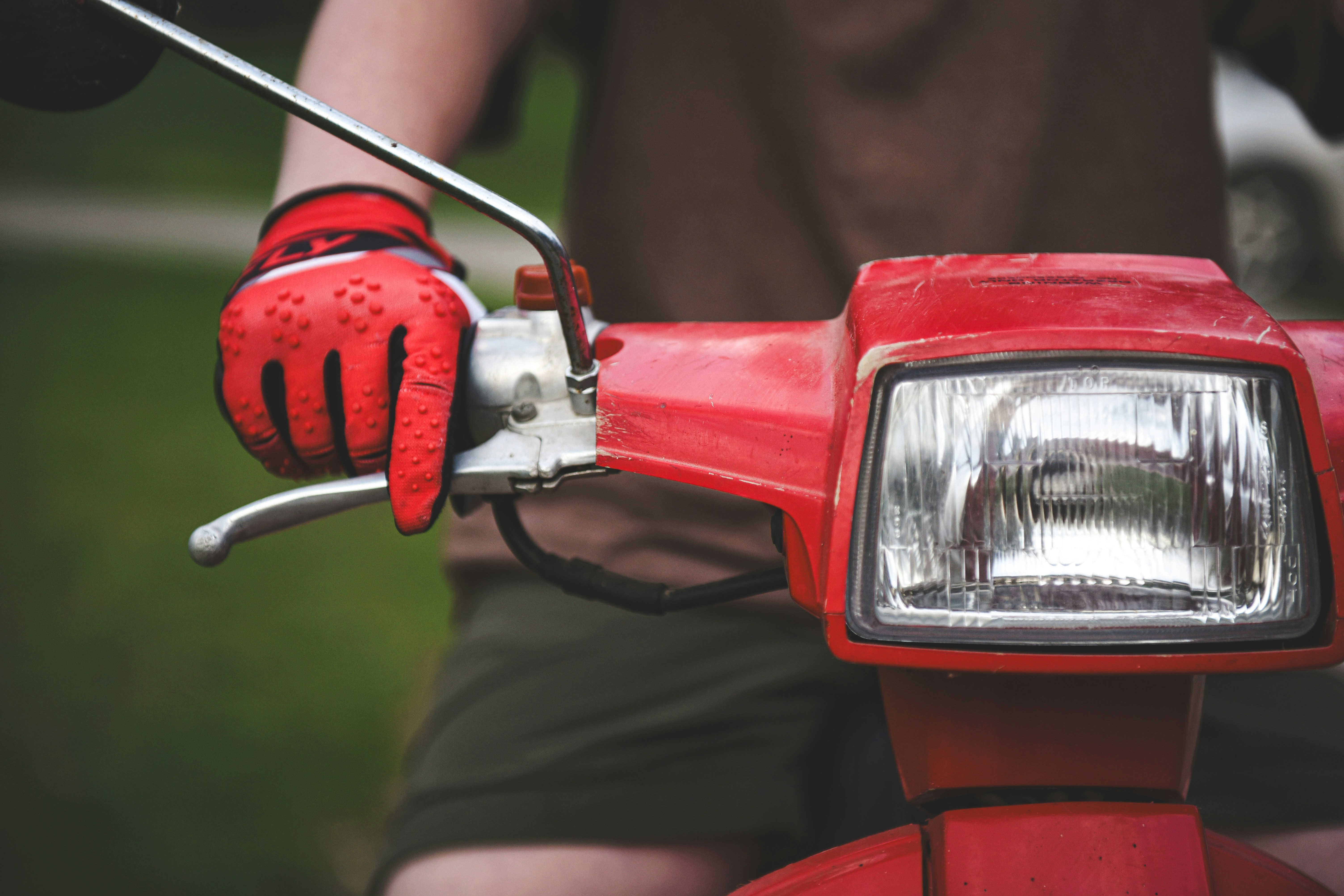 Front View of Red Scooter Headlamp with Gloved Hand Gripping Handlebar