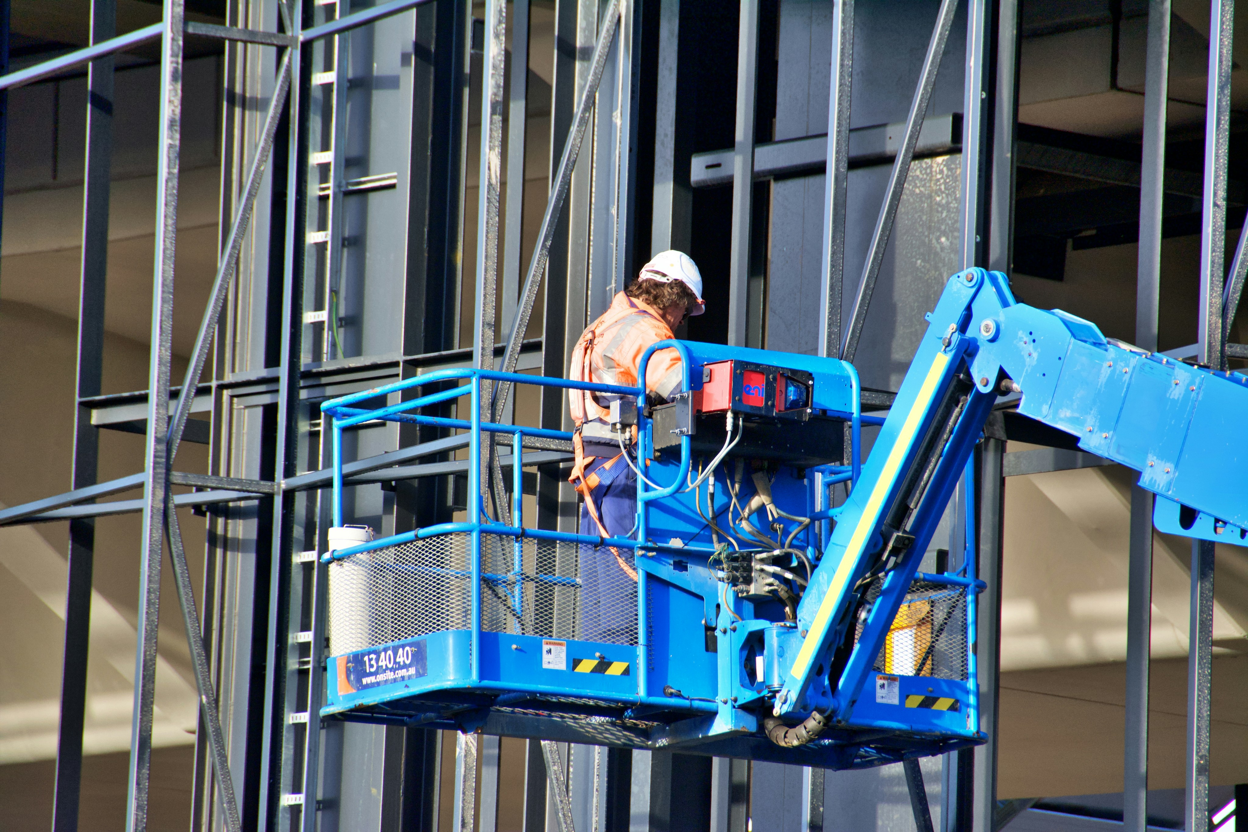 Worker in blue suspended platform at a construction site