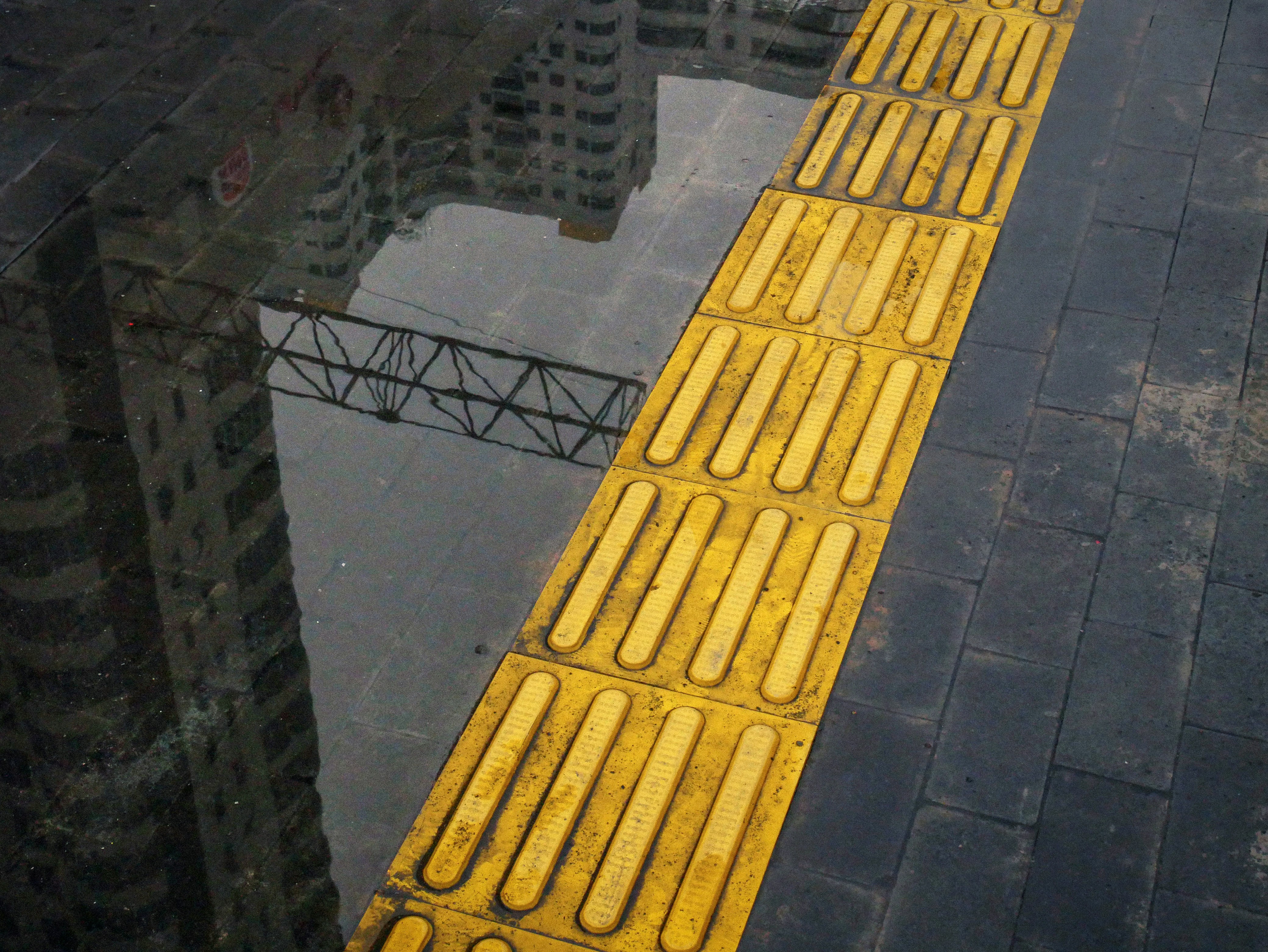 Yellow Tactile Path Crossing a Modern Glass Street Surface