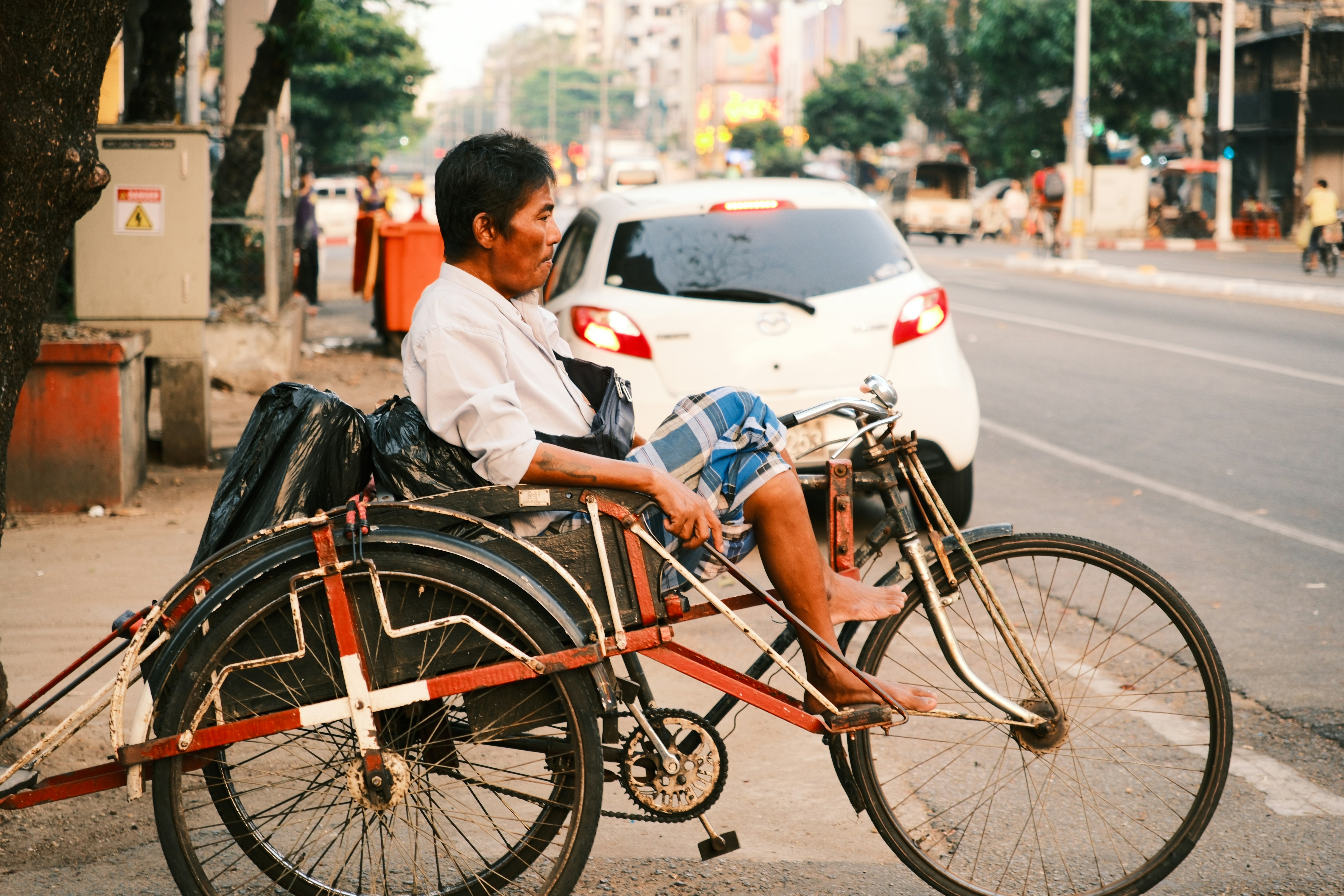 Riding the City: A street-side moment with a barefoot rider on a tricycle bike